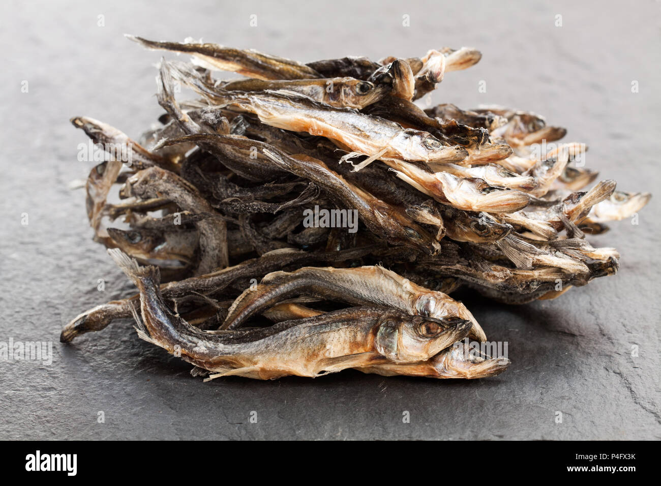 Heap of dried fishes on black stone background Stock Photo - Alamy