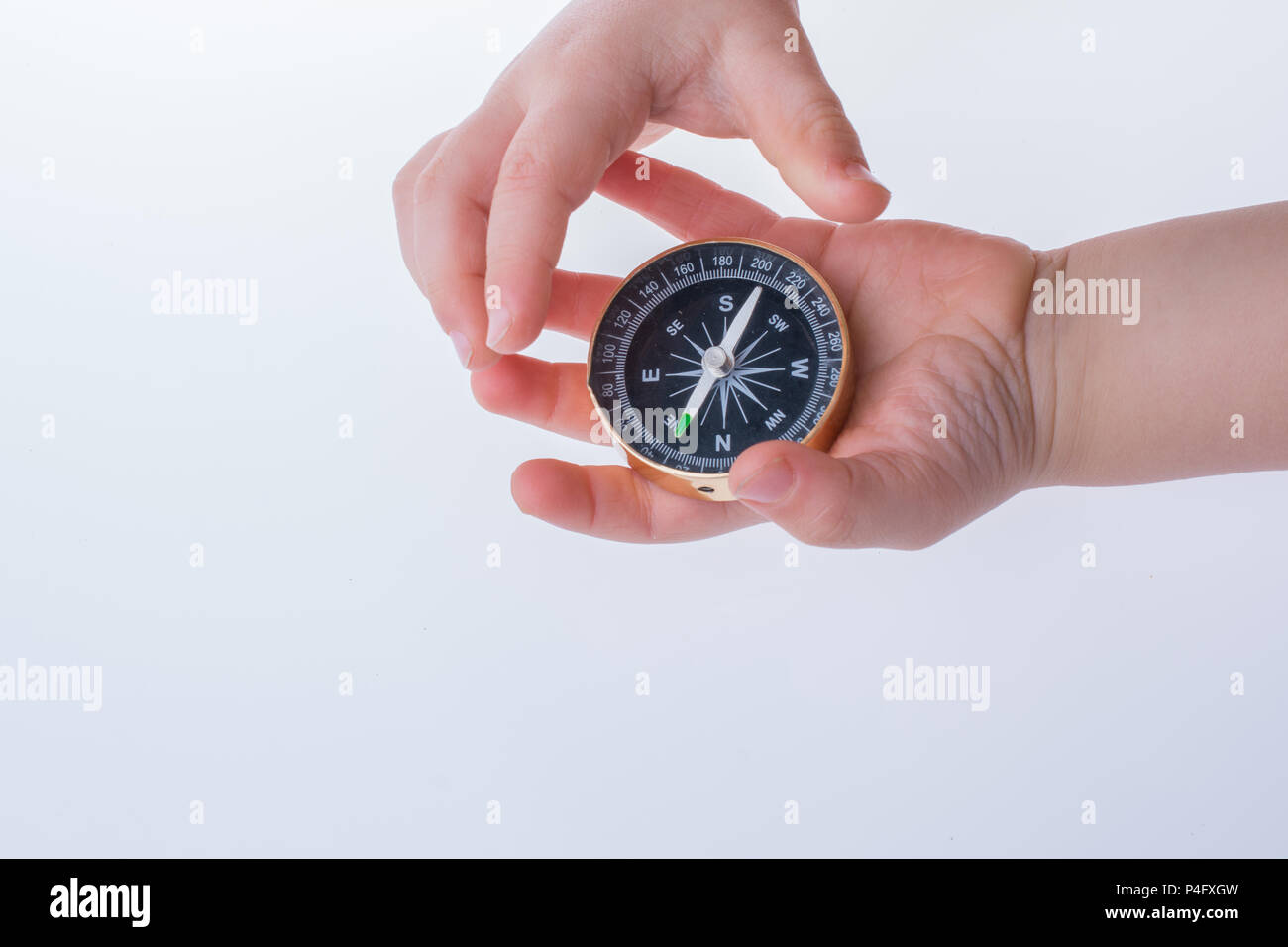 Child hand holding a compass on a white background Stock Photo - Alamy