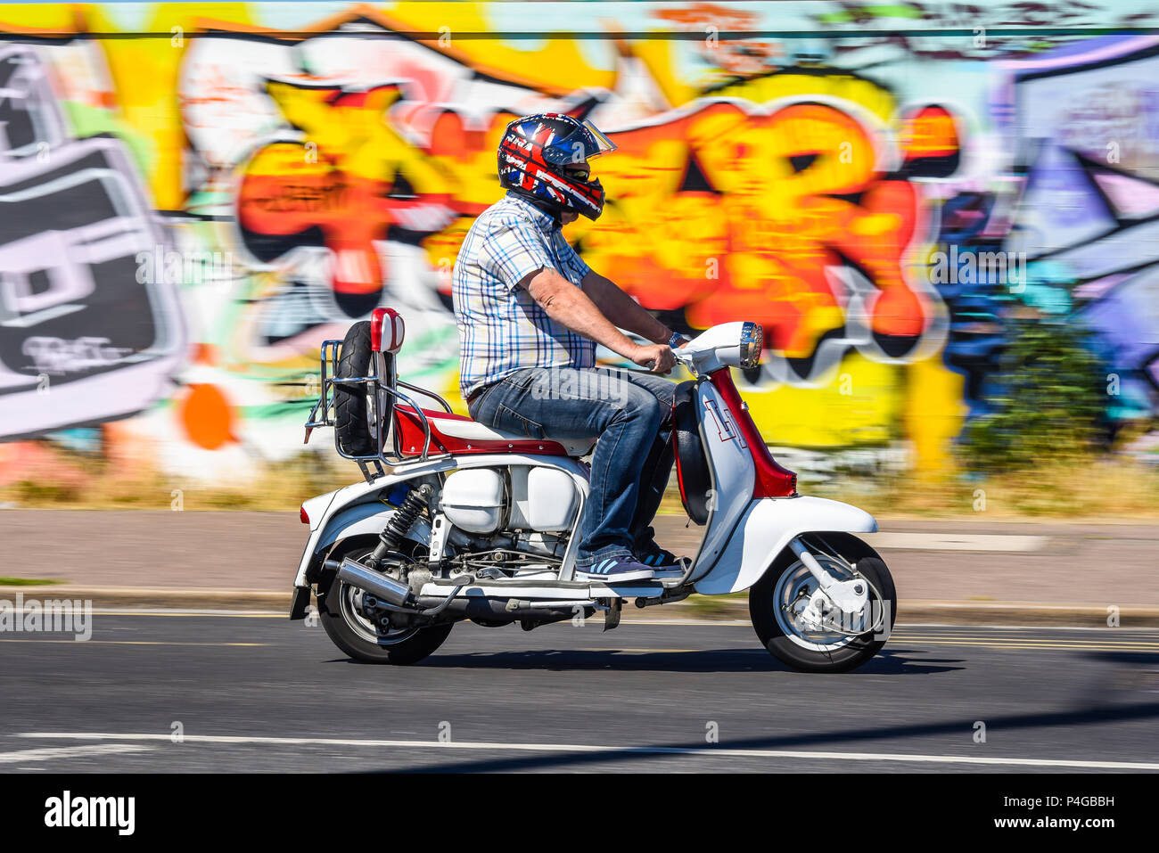 Motor scooter rider with British Union Flag helmet riding along Eastern ...