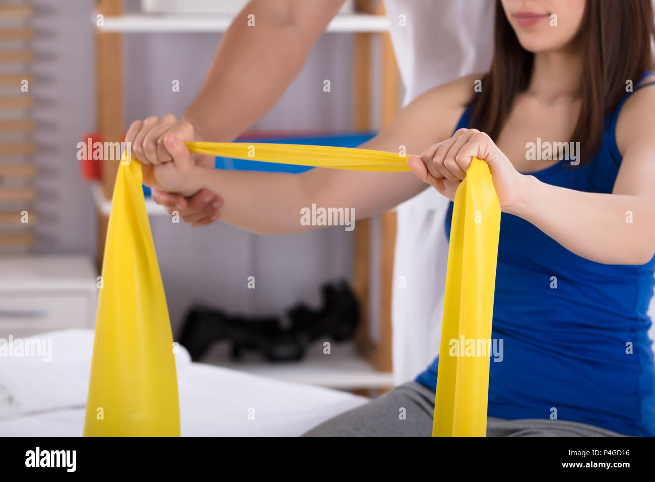 Physiotherapist Assisting Woman While Doing Exercise With Yellow ...