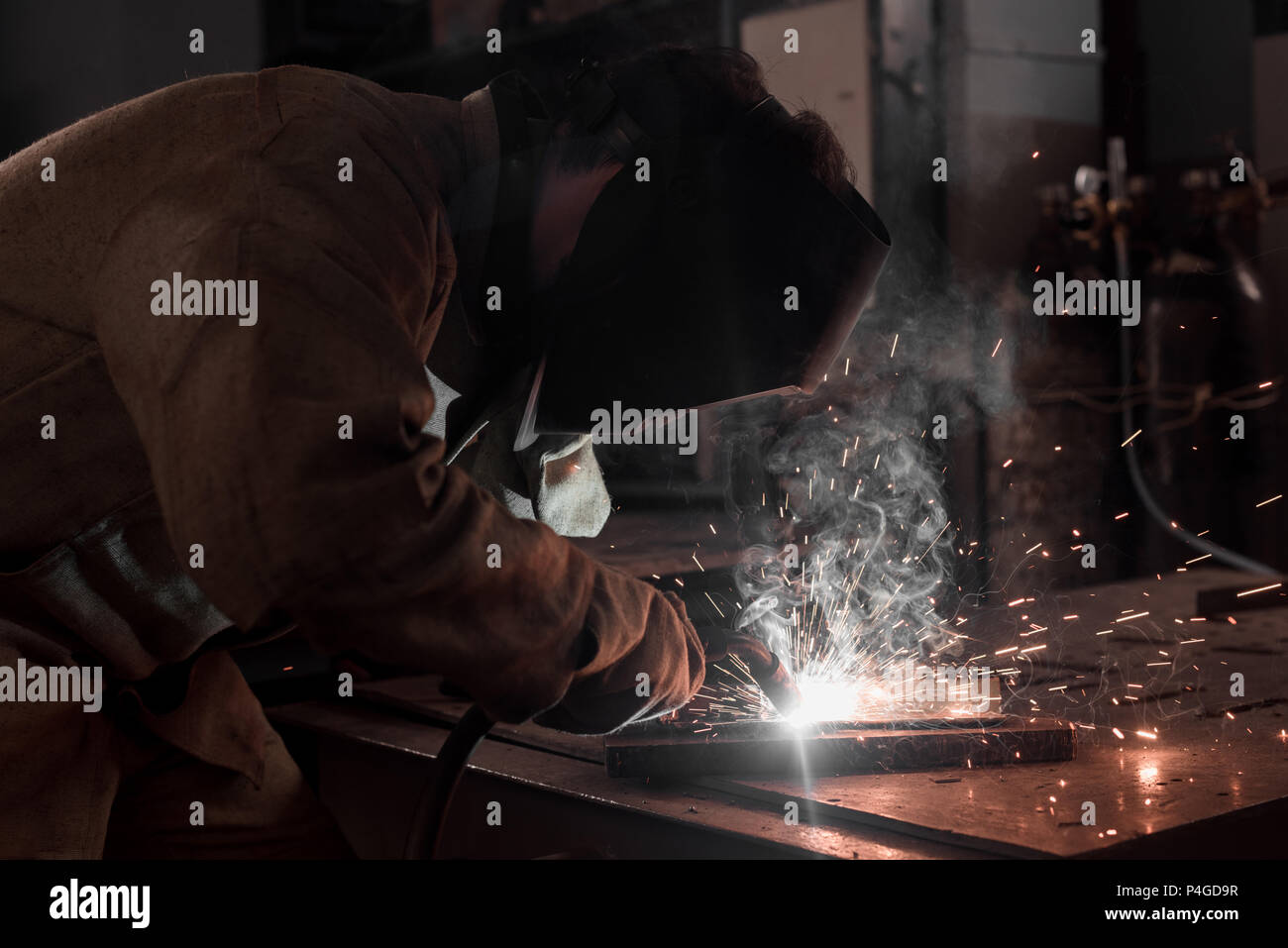 side view of worker in protection mask welding metal at factory Stock ...