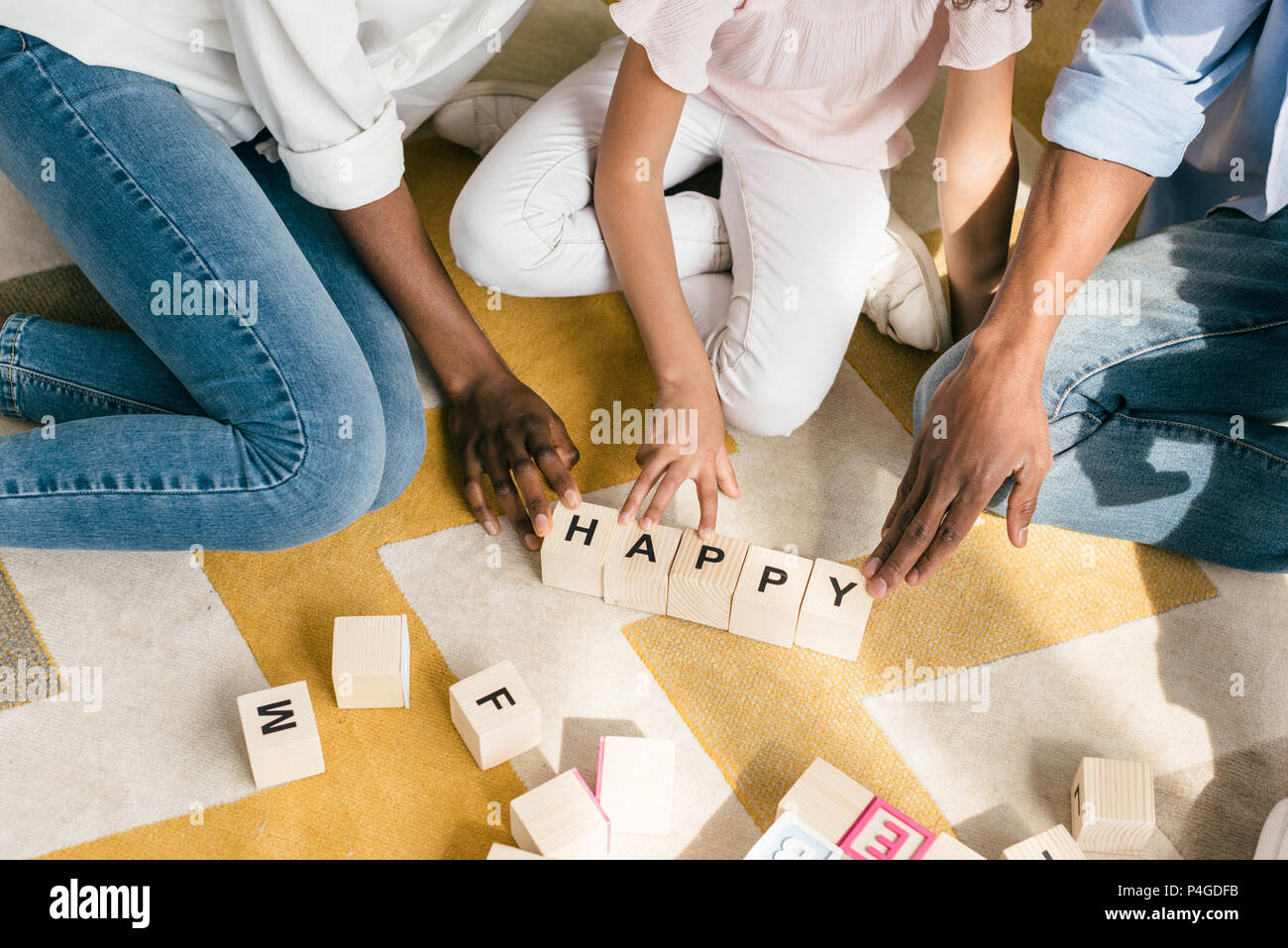 partial view of african american parents and daughter sitting on floor ...
