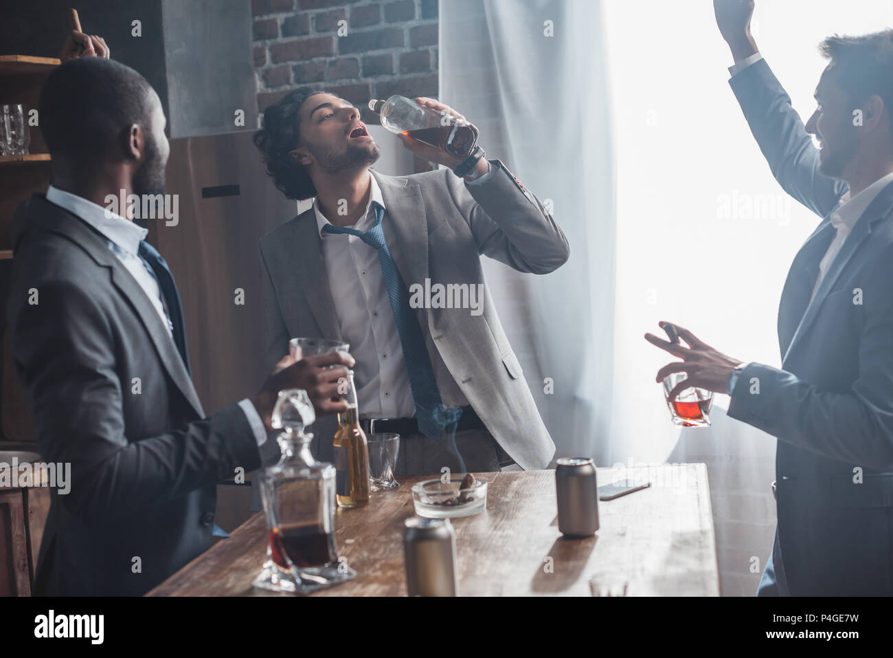 happy multiethnic friends in suits drinking alcohol and smoking cigars ...