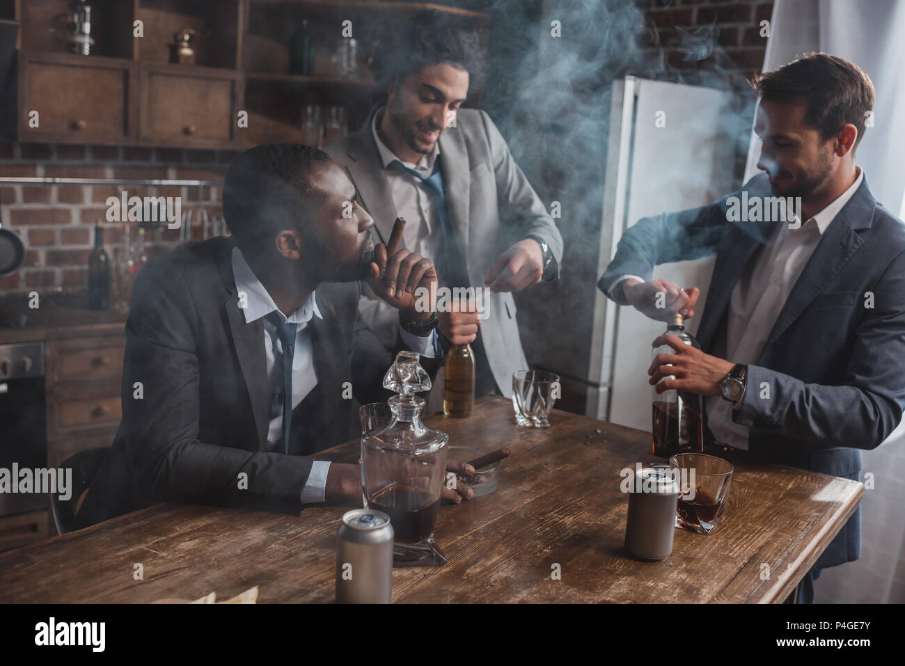 young multiethnic businessmen smoking cigars and drinking alcoholic ...