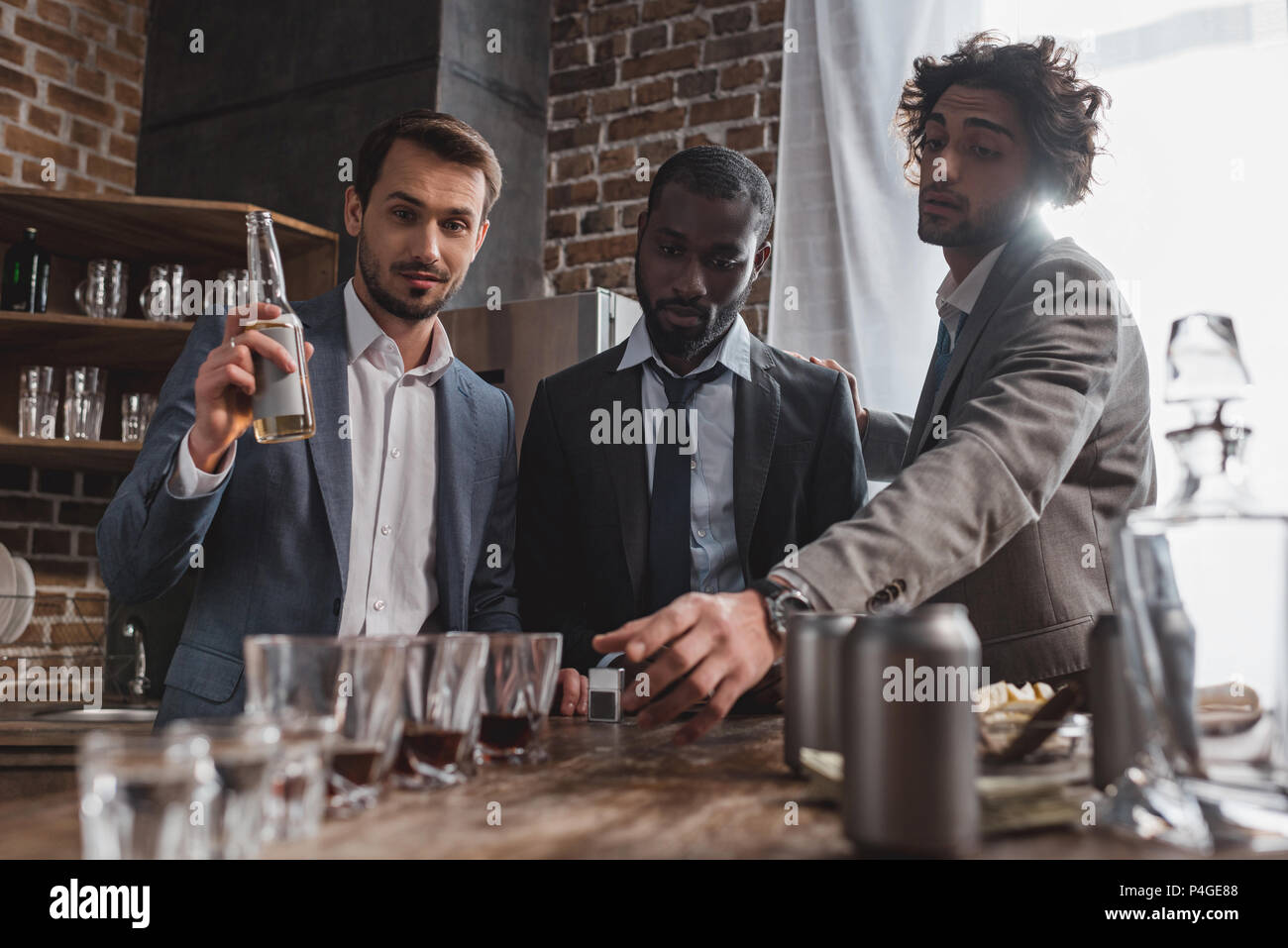 young multiethnic friends in suits drinking alcohol beverages together ...