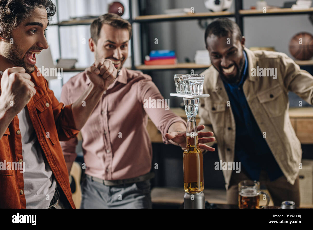 excited multiethnic men building tower from bottles and glasses while ...