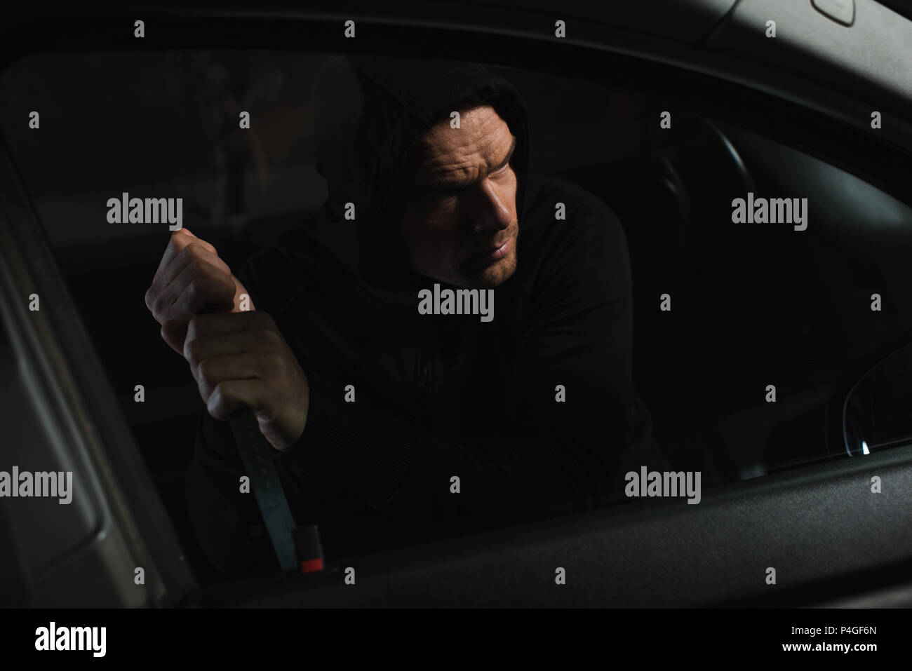 serious male robber in black hoodie intruding car by crowbar Stock ...