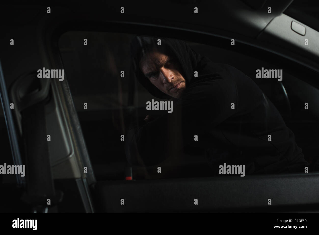 serious male robber trying to break car window by elbow Stock Photo - Alamy