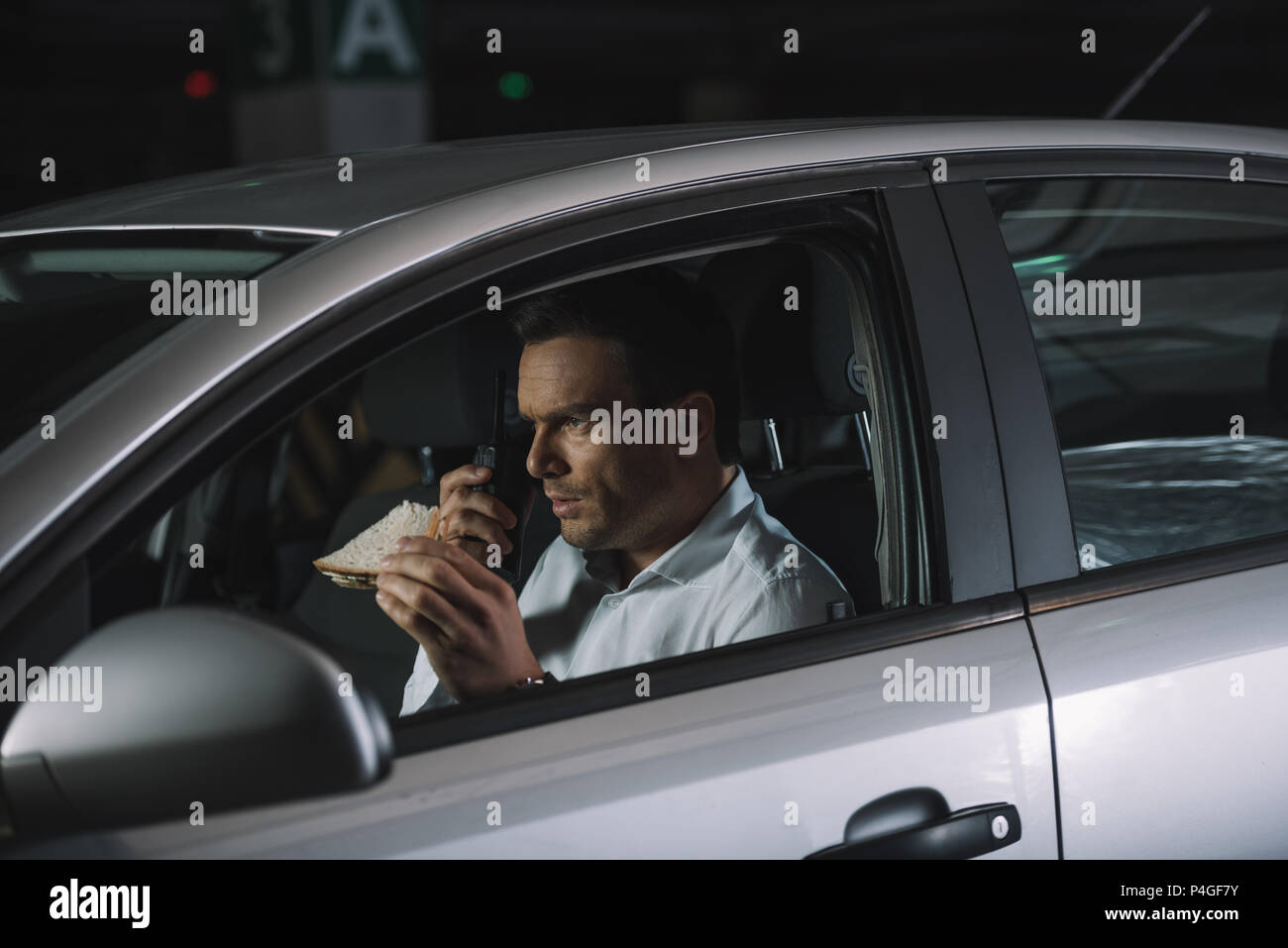 male private detective having lunch and using talkie walkie in car ...
