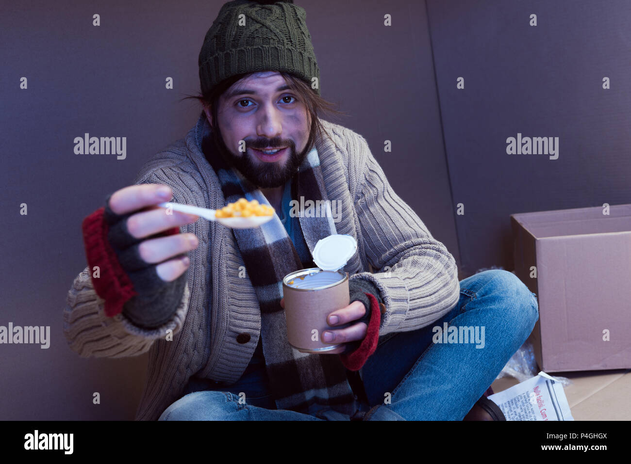 smiling homeless man eating canned food in cardboard box Stock Photo ...