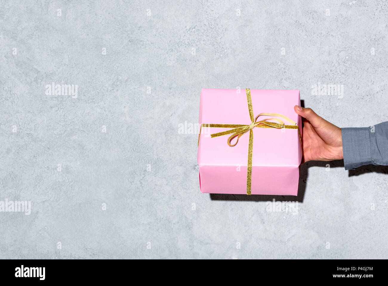 Close-up view of man giving gift box on grey background Stock Photo - Alamy