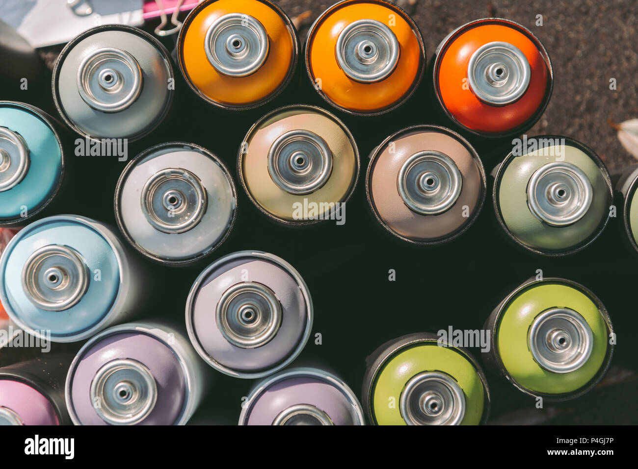 top view of cans with colorful spray paint for graffiti on asphalt ...