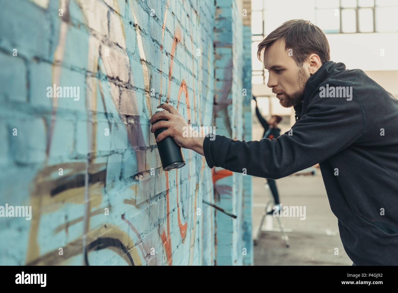 street artist painting colorful graffiti on wall of building Stock ...