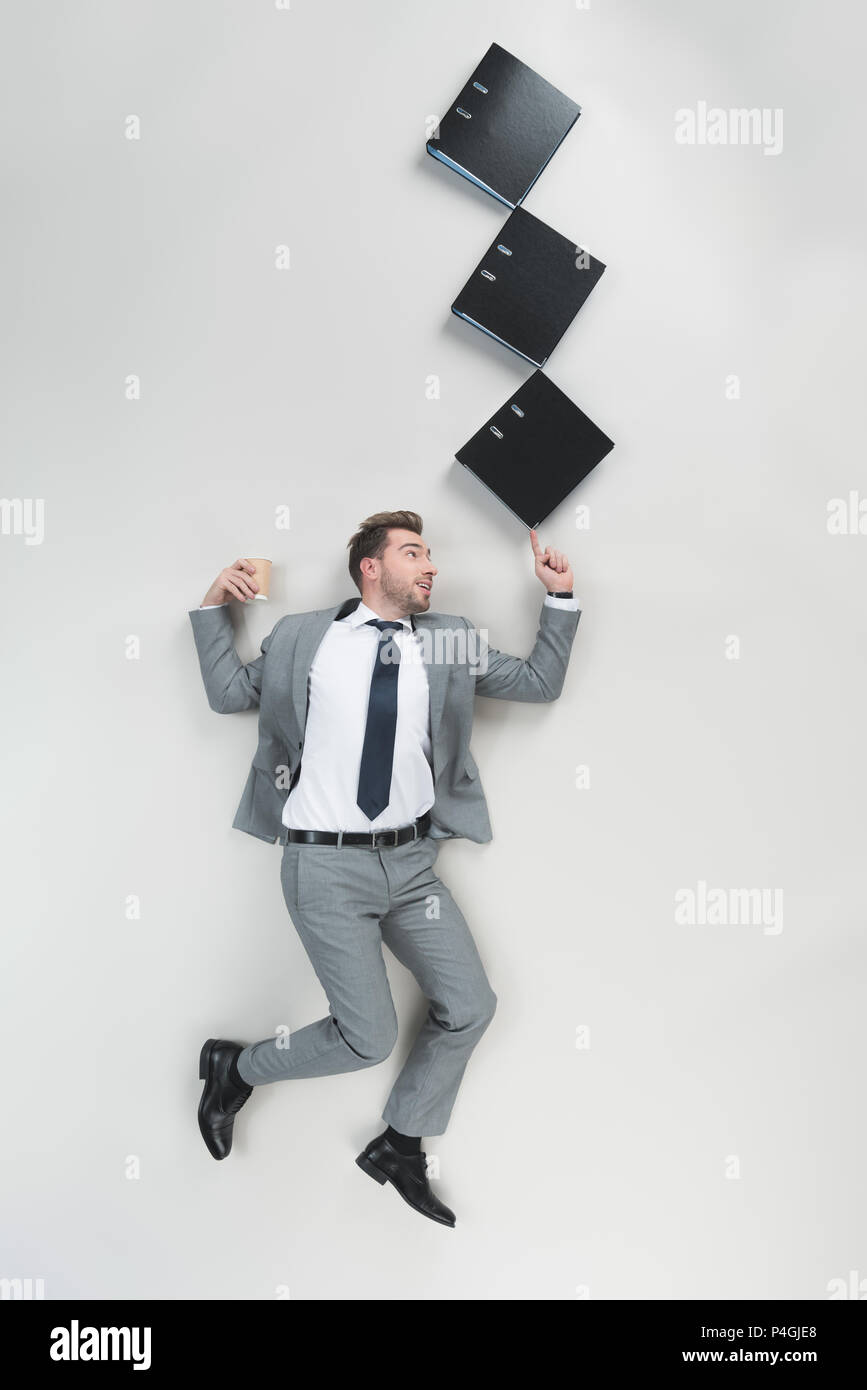 overhead view of businessman with coffee to go holding stack of folders ...