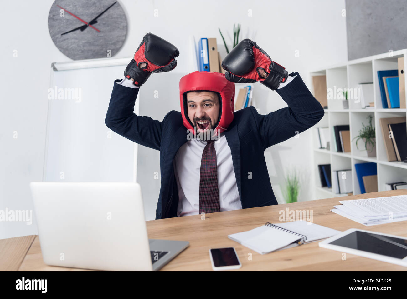 portrait of excited businessman in boxing gloves and helmet at ...