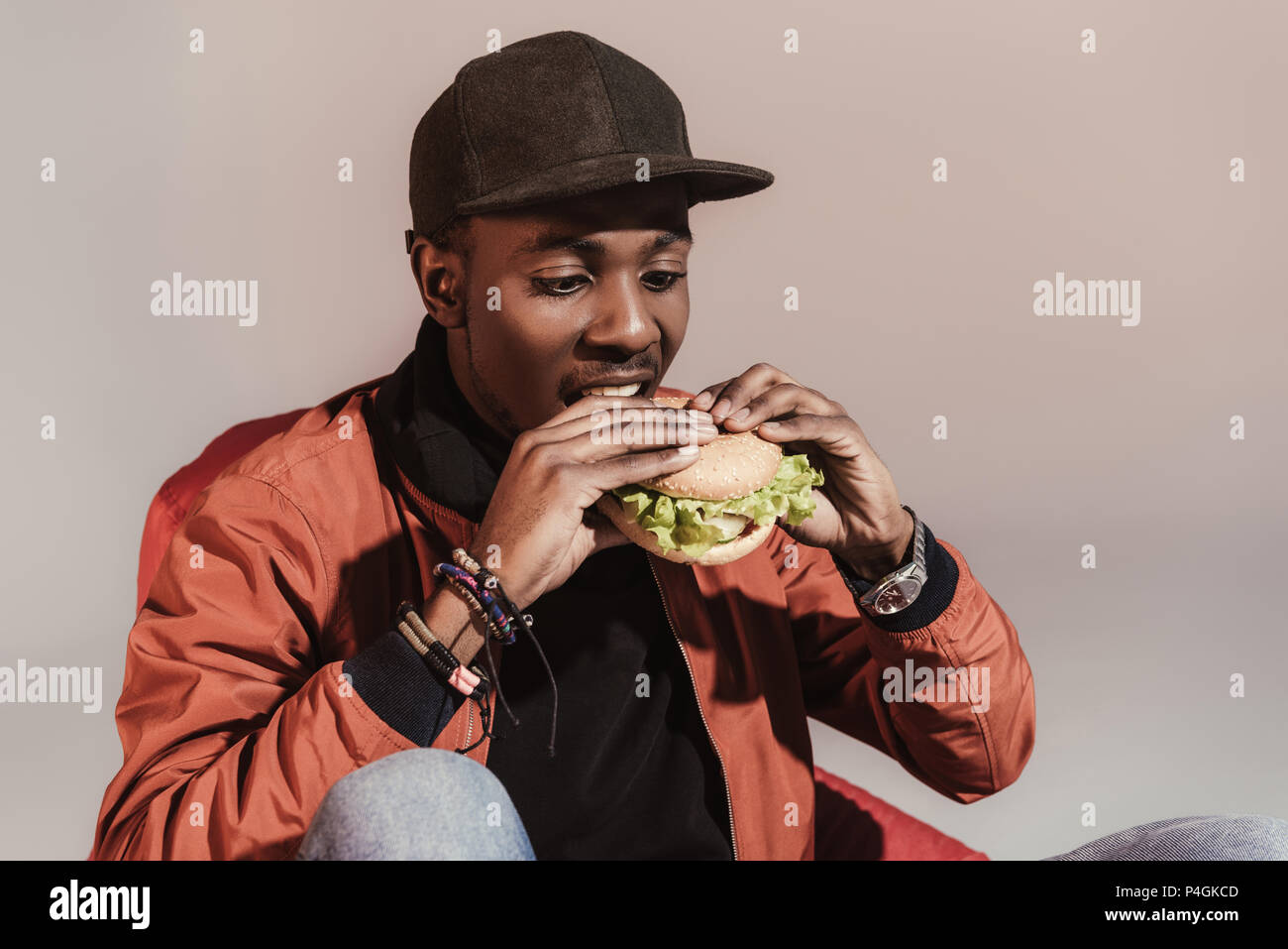 young african american man eating hamburger isolated on grey Stock ...