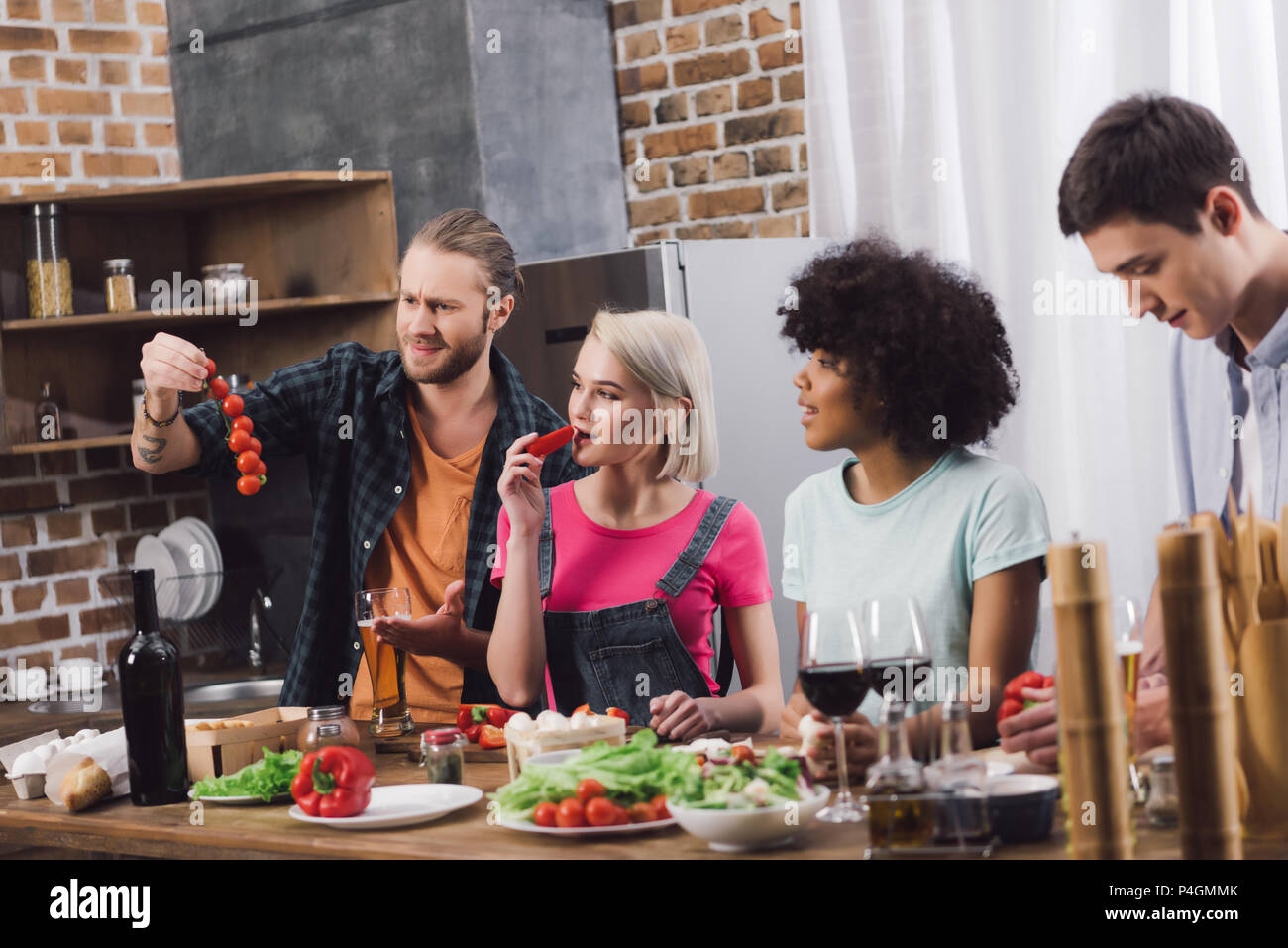 multiethnic friends tasting some food while cooking in kitchen Stock ...