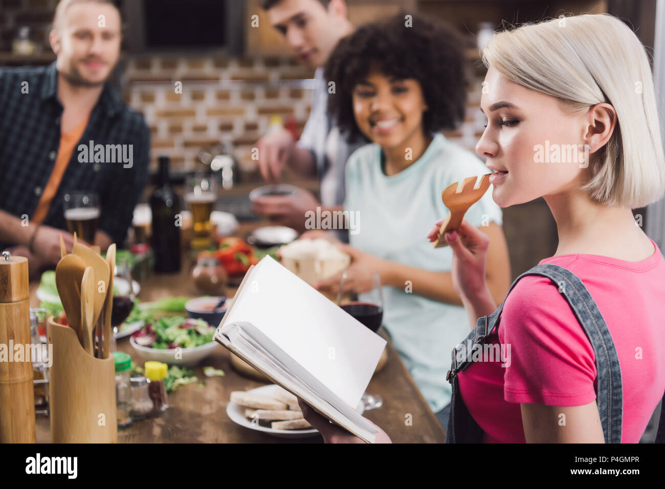 girl holding recipe book and biting wooden spatula Stock Photo - Alamy
