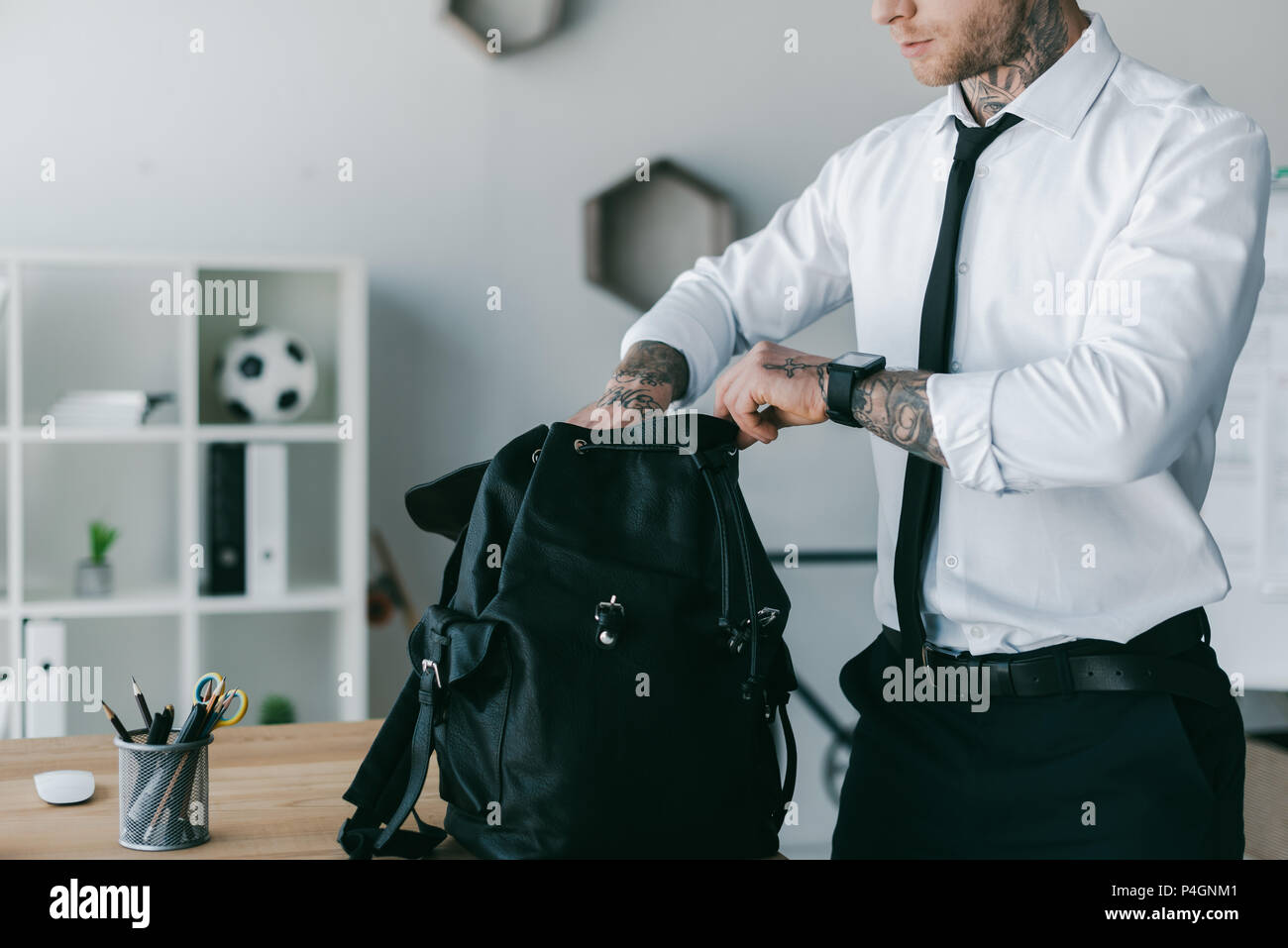 cropped shot of young tattooed businessman opening backpack at ...