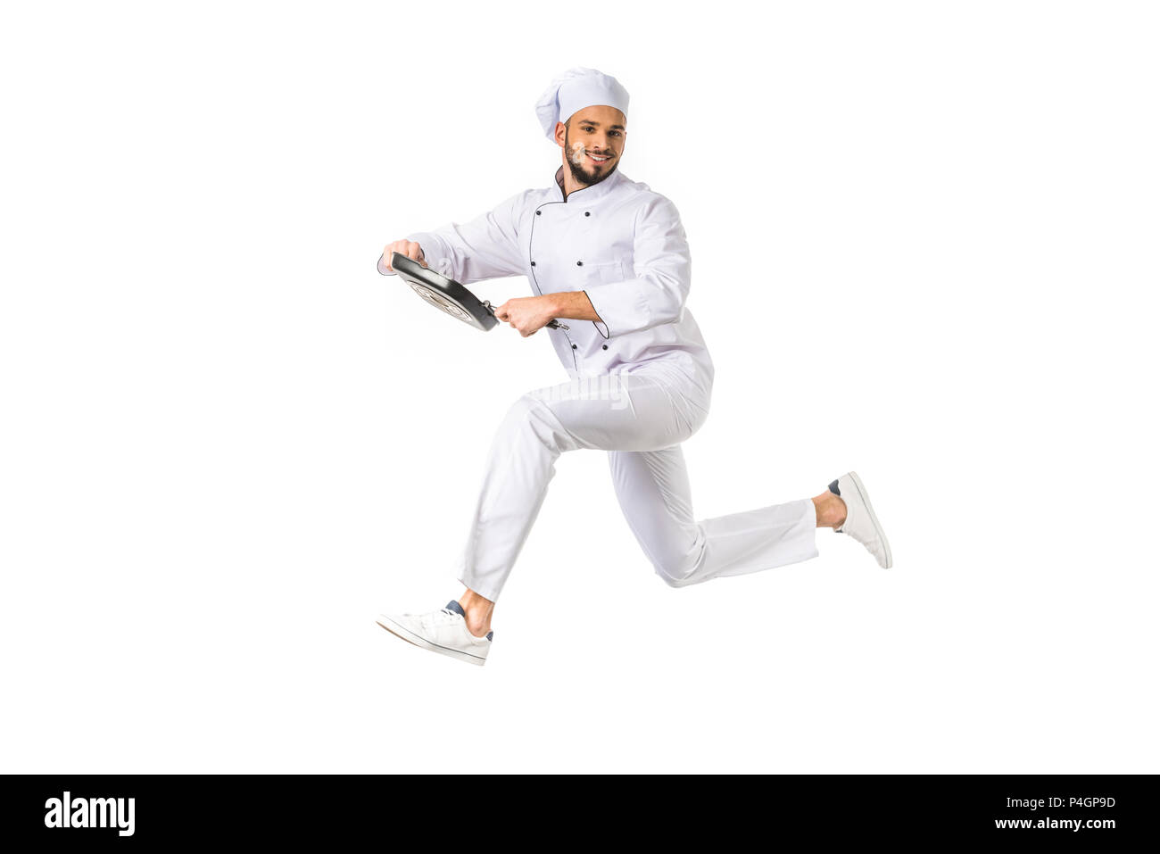 smiling chef with frying pan jumping and looking at camera isolated on ...