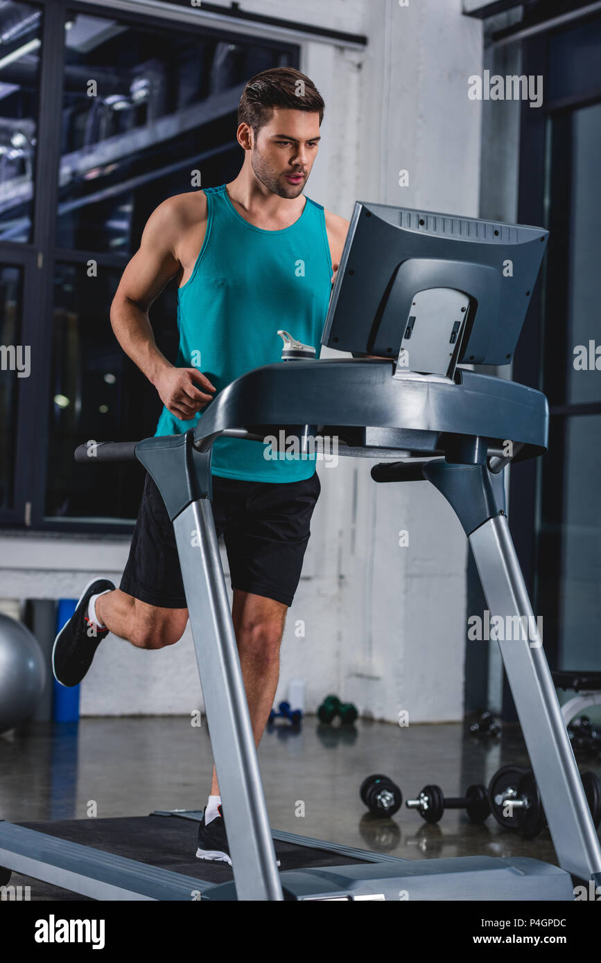 athletic man running on treadmill in sports center Stock Photo - Alamy