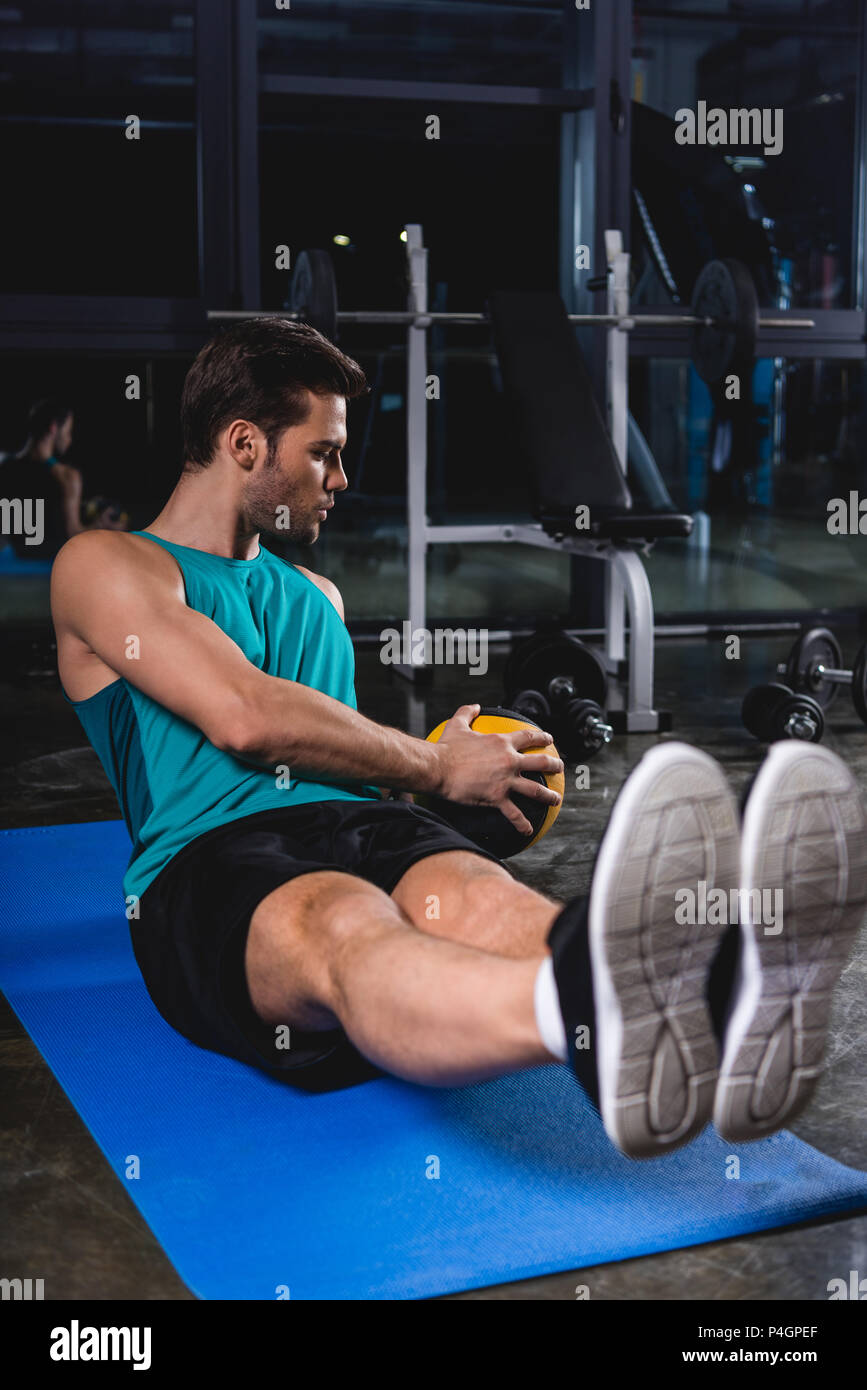 sportsman training with medicine ball on yoga mat in sports center ...