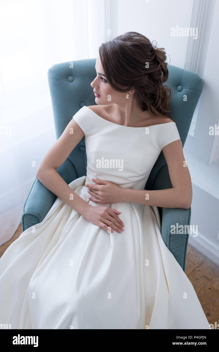 attractive young bride in wedding dress sitting in armchair Stock Photo ...