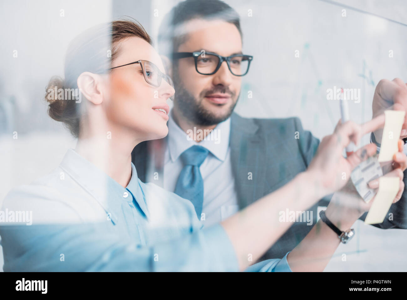 successful businesspeople drawing graphs on glass presentation board ...