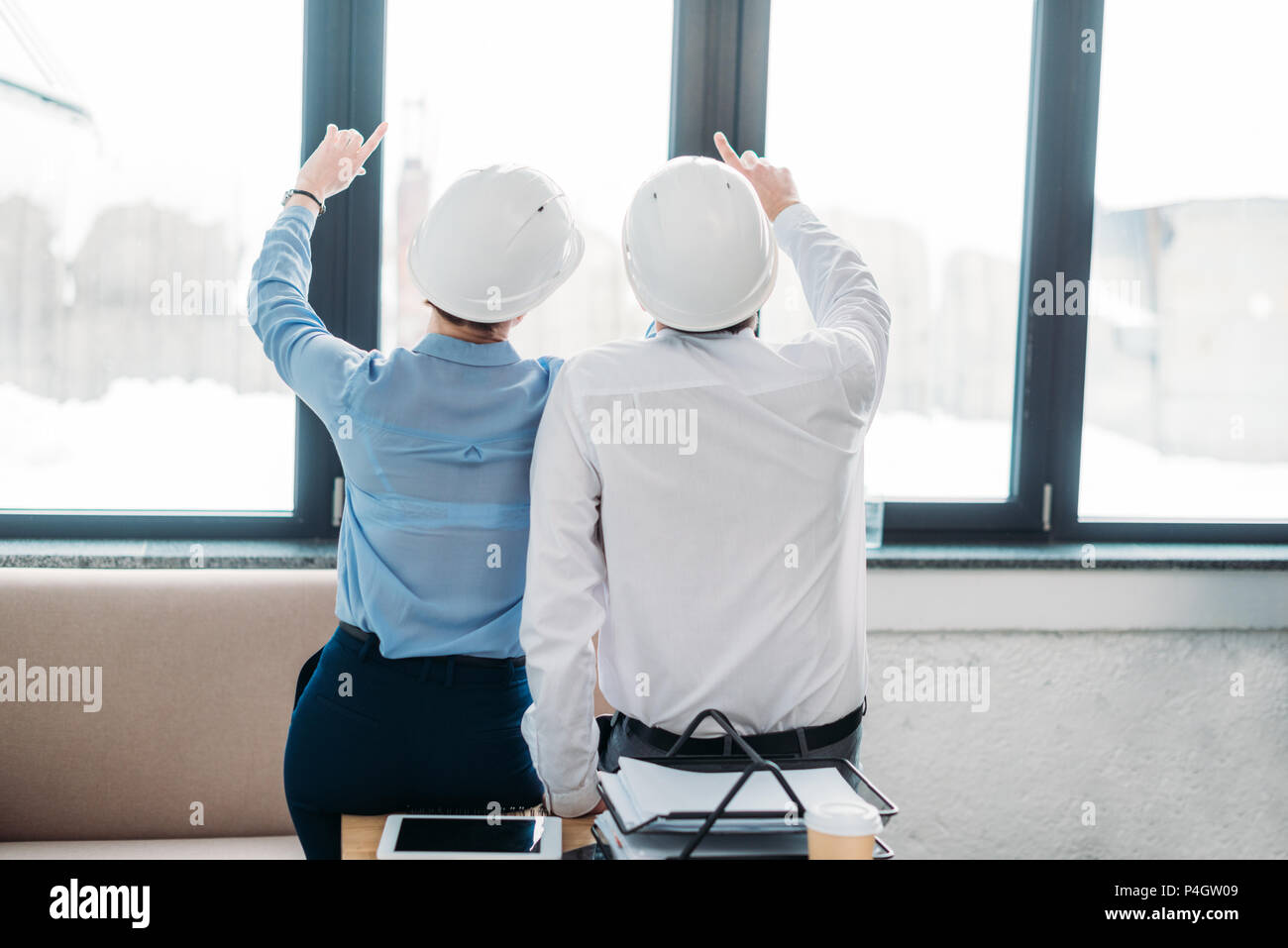 back view of architects pointing up through window from office Stock ...