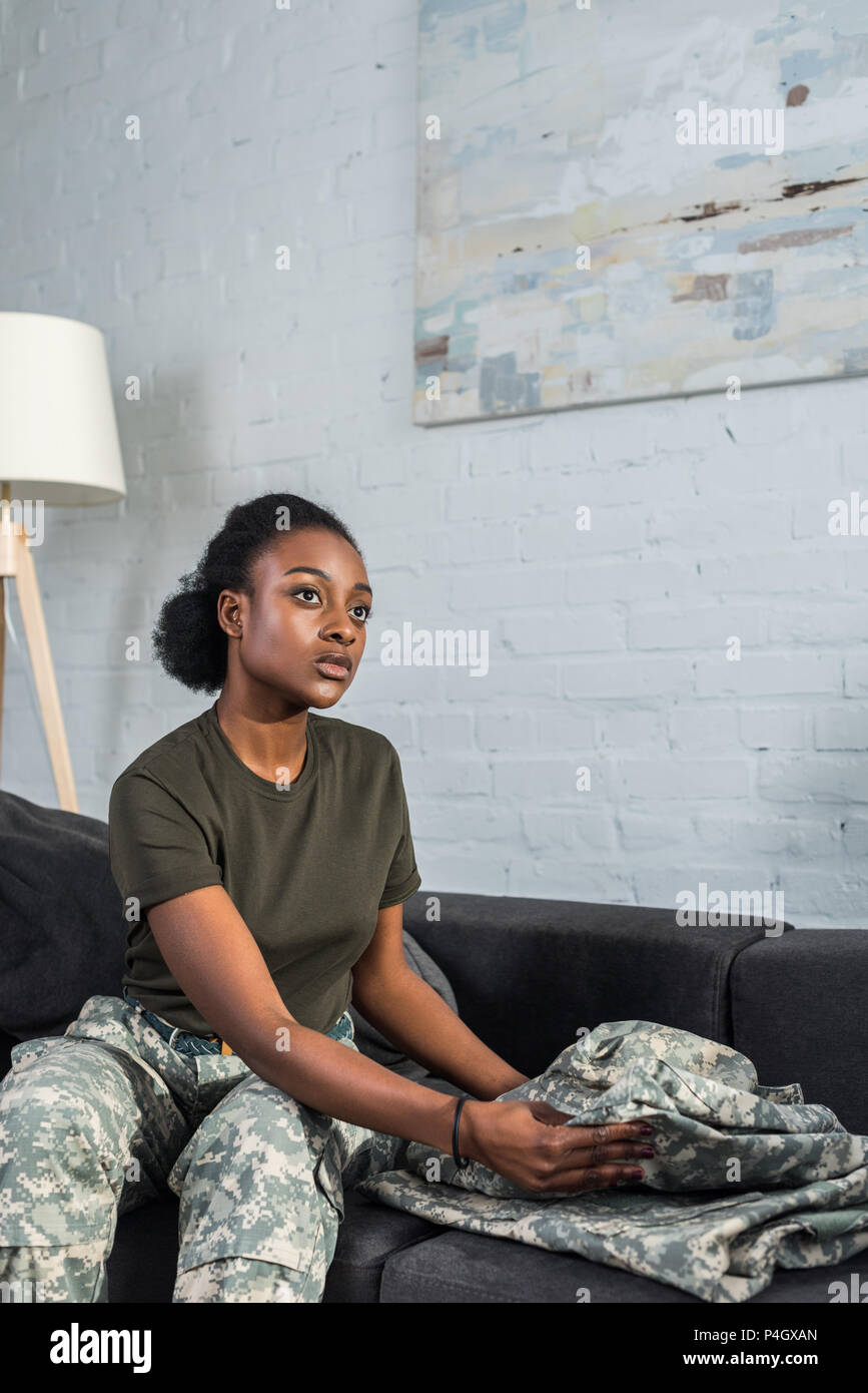 Female army soldier folding camouflage clothes on sofa Stock Photo - Alamy