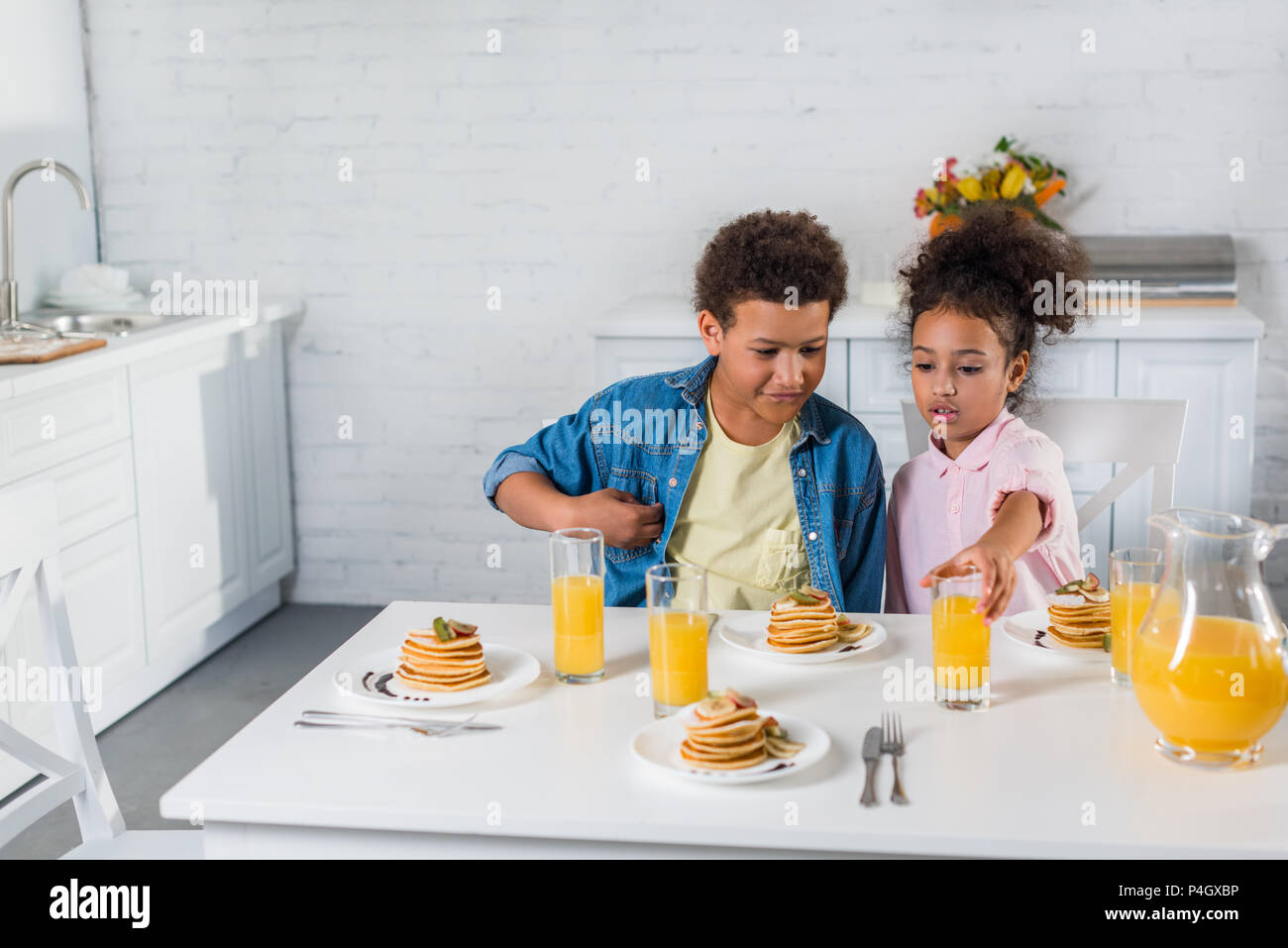 African american brother and sister eating breakfast with pancakes ...