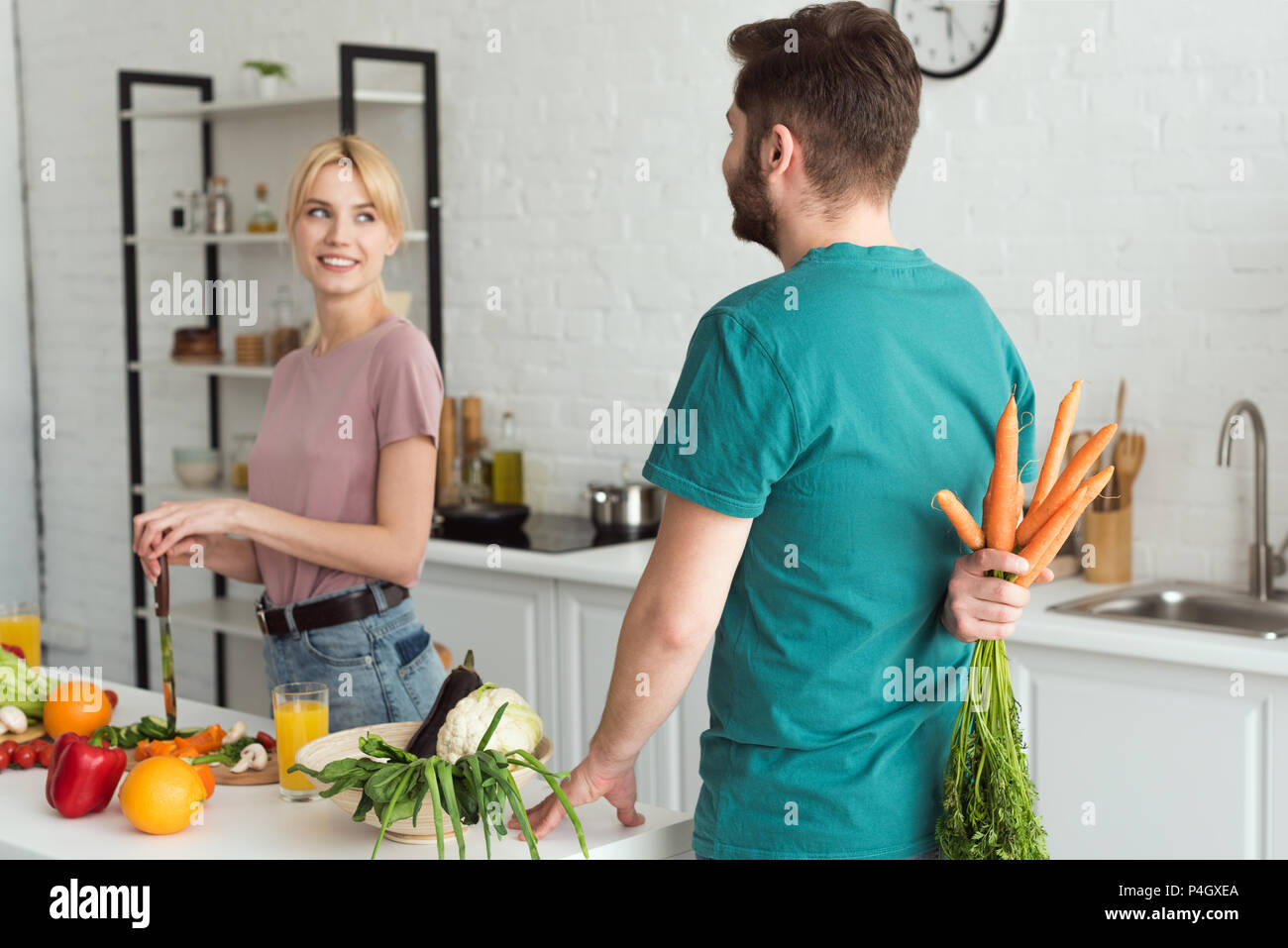 vegan boyfriend hiding bouquet of carrots from girlfriend at kitchen ...