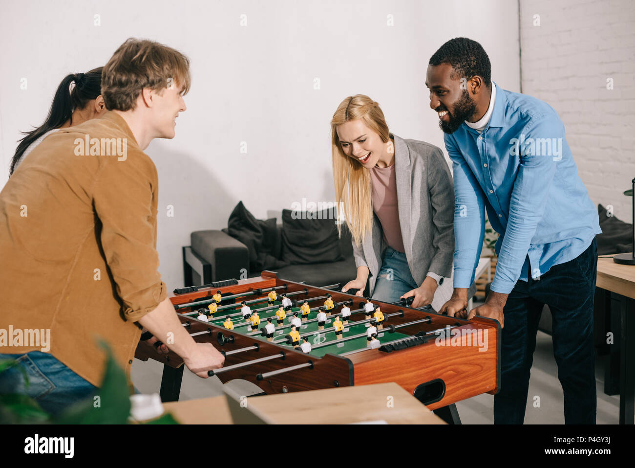 smiling multiethnic business colleagues playing table football in ...