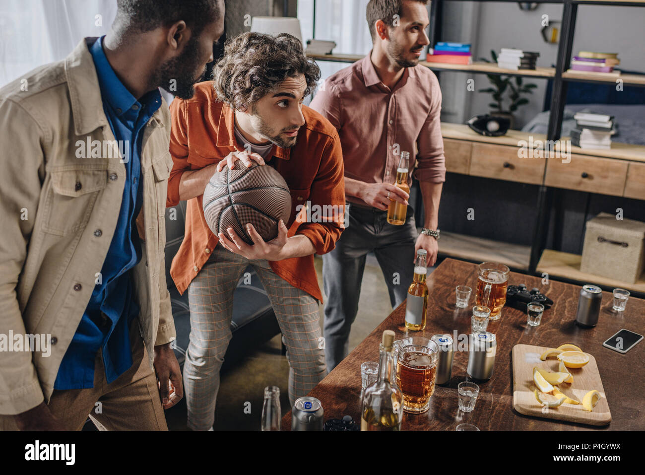 young multiethnic men playing with basketball ball and drinking beer ...
