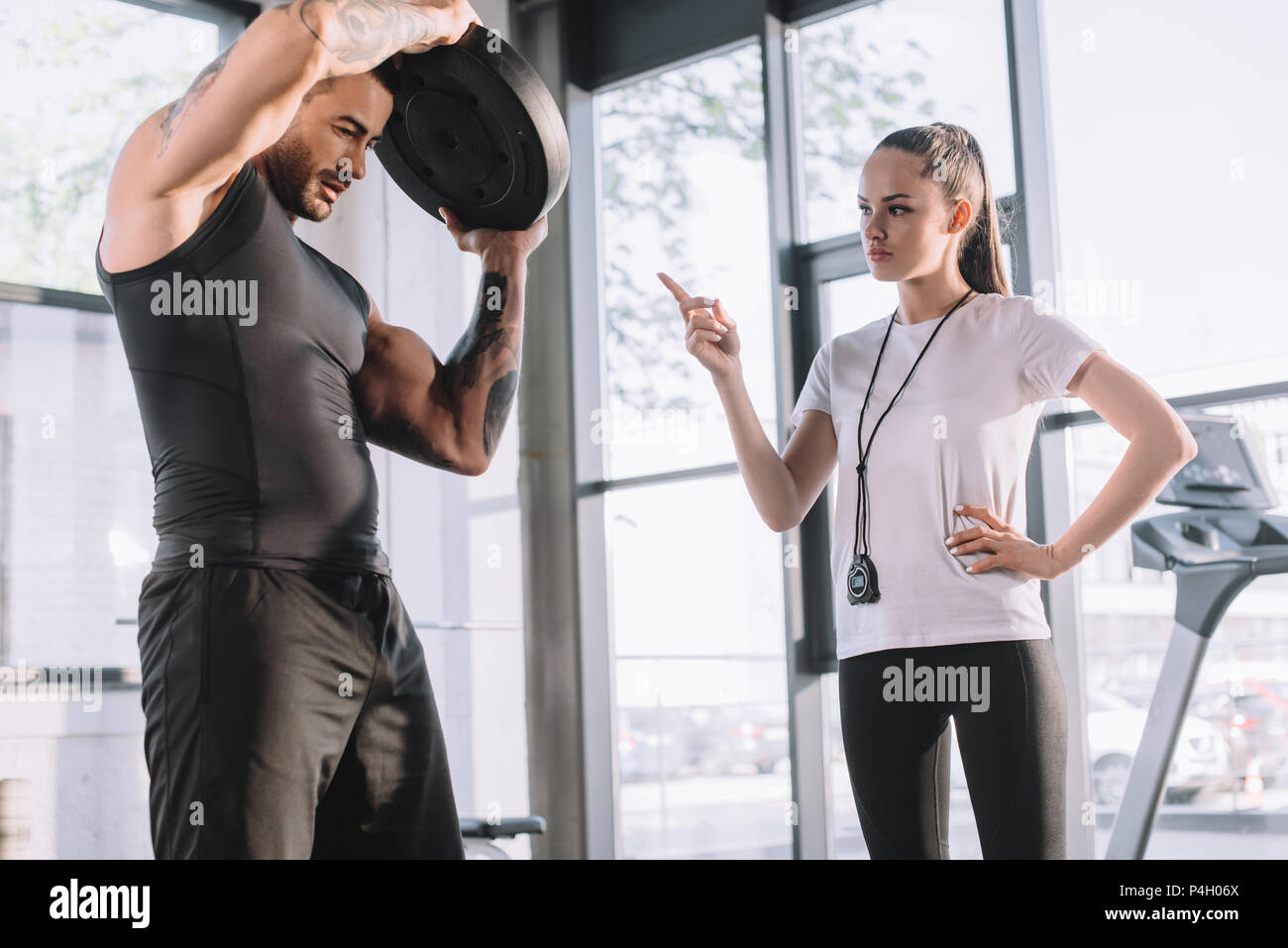 female personal trainer counting while sportsman doing exercises with ...