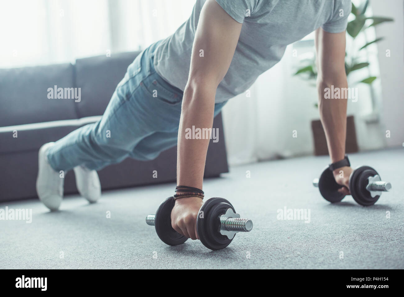 partial view of young man doing push ups with dumbbells at home Stock ...