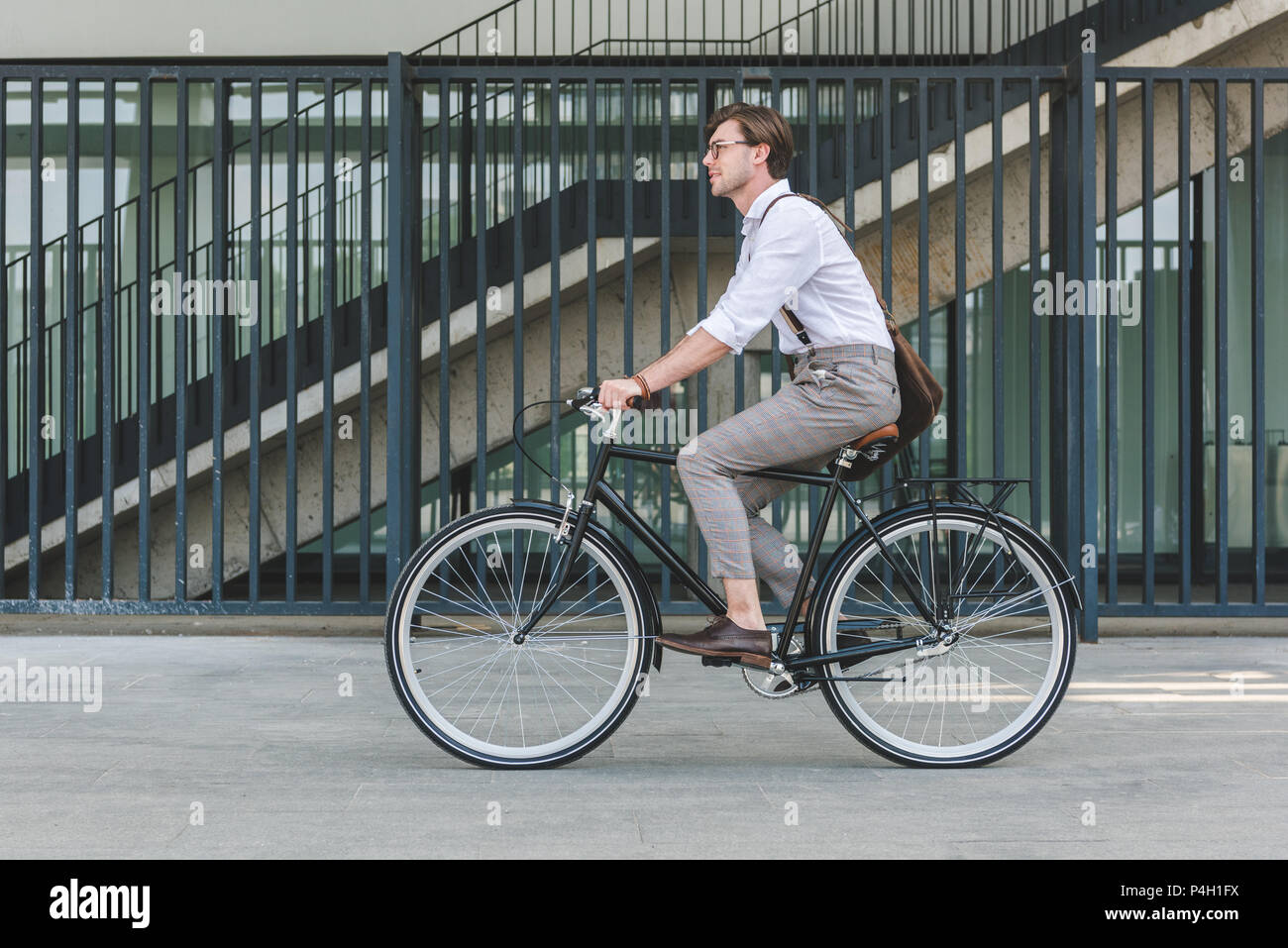 side view of handsome young man riding vintage bicycle on city street ...