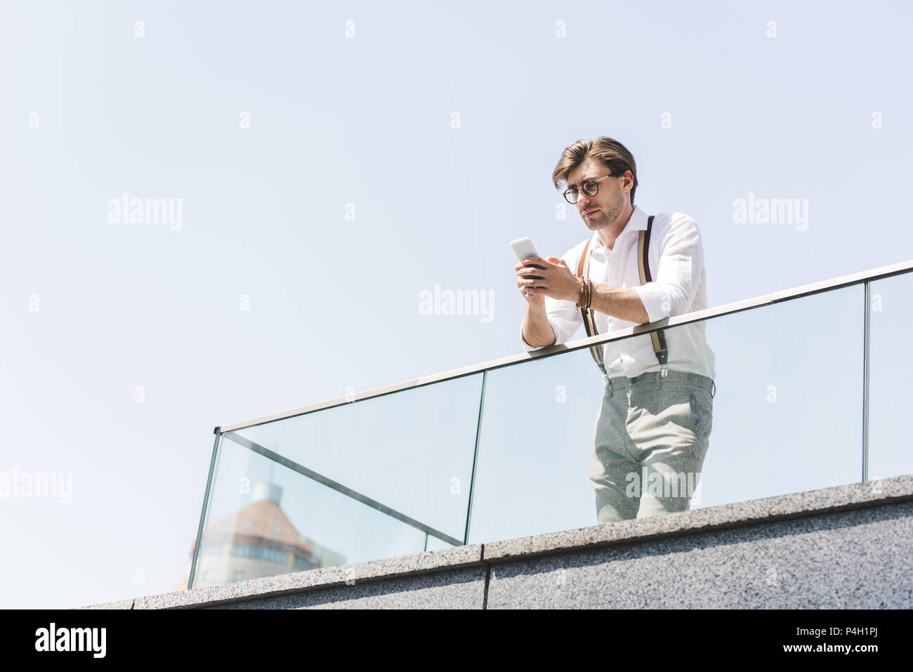 bottom view of handsome young man using smartphone on balcony Stock ...