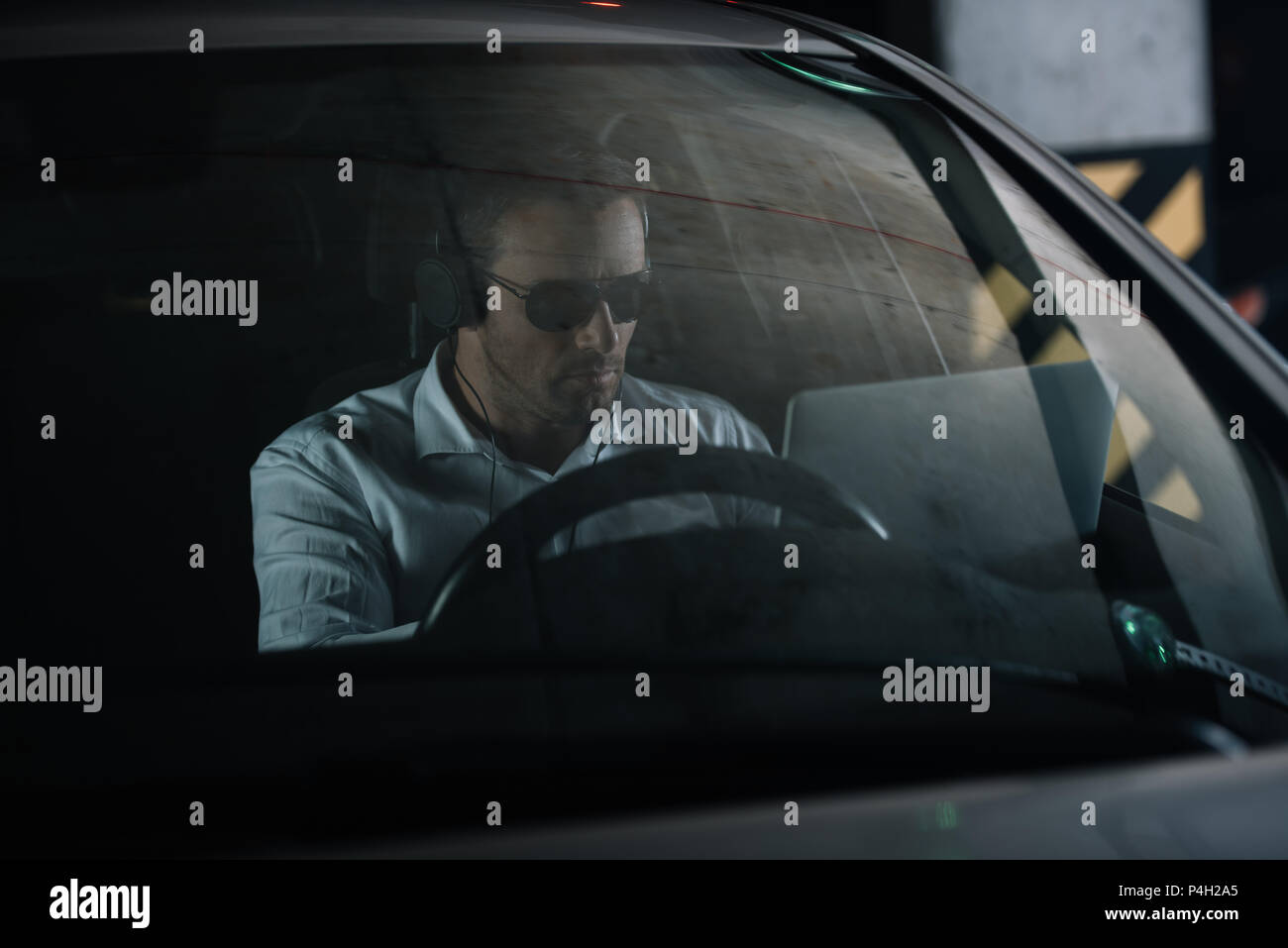 focused male private detective in headphones doing surveillance with ...