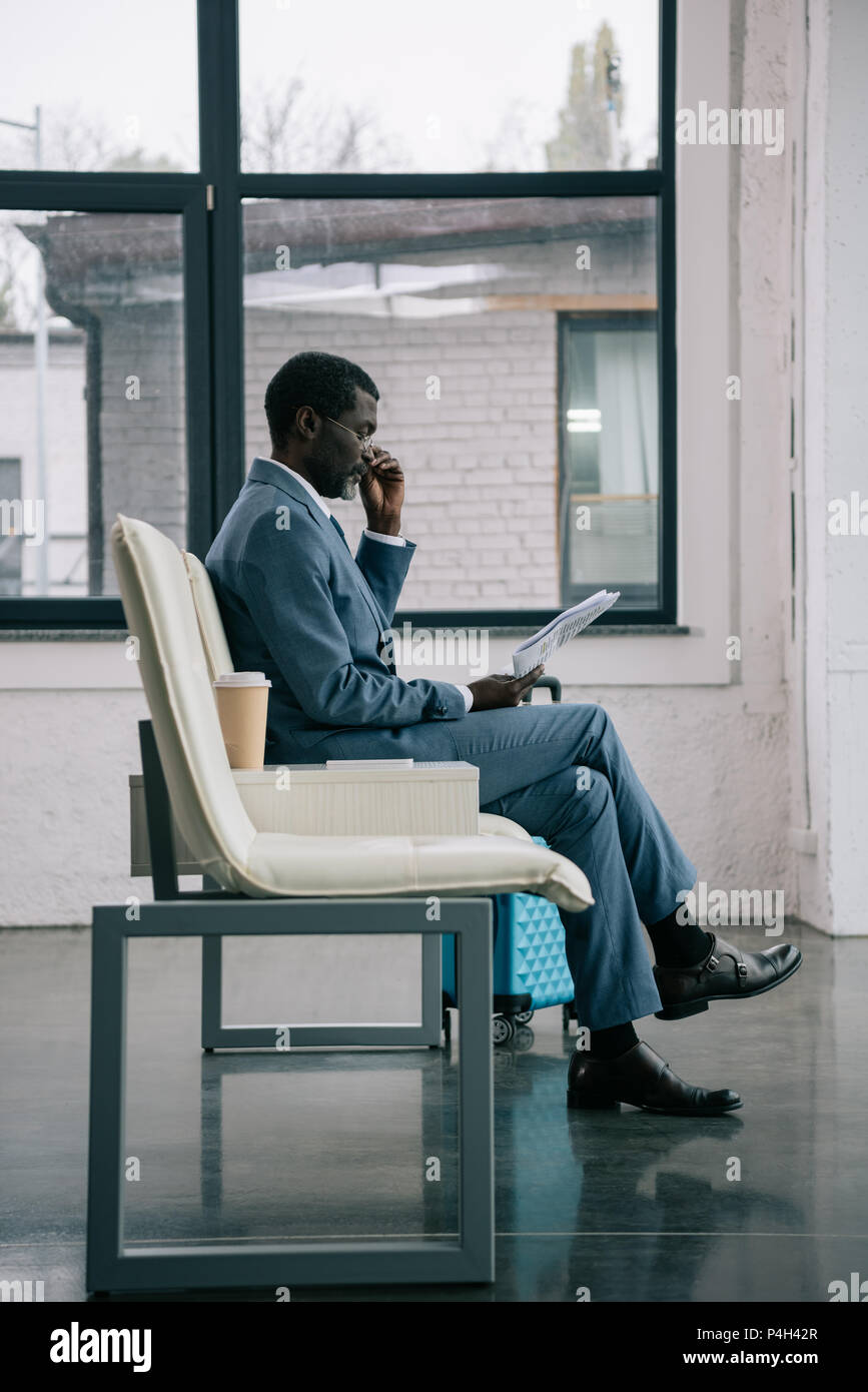 Side view of Middle aged Businessman reading newspaper in the airport ...