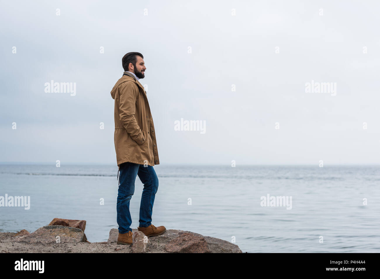lonely man standing on rocky seashore Stock Photo - Alamy
