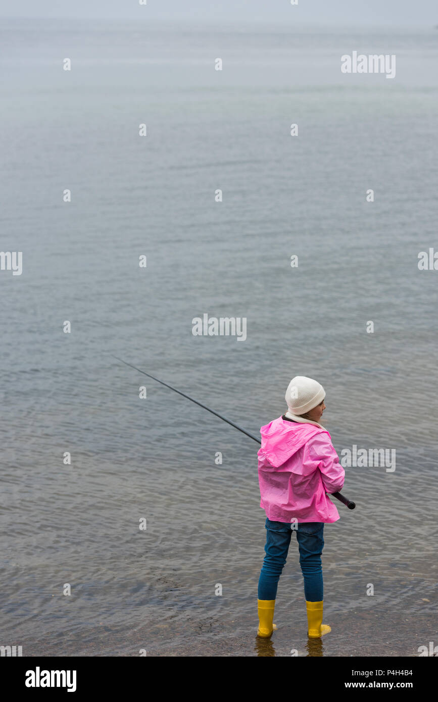 little girl in raincoat and boots fishing alone Stock Photo - Alamy
