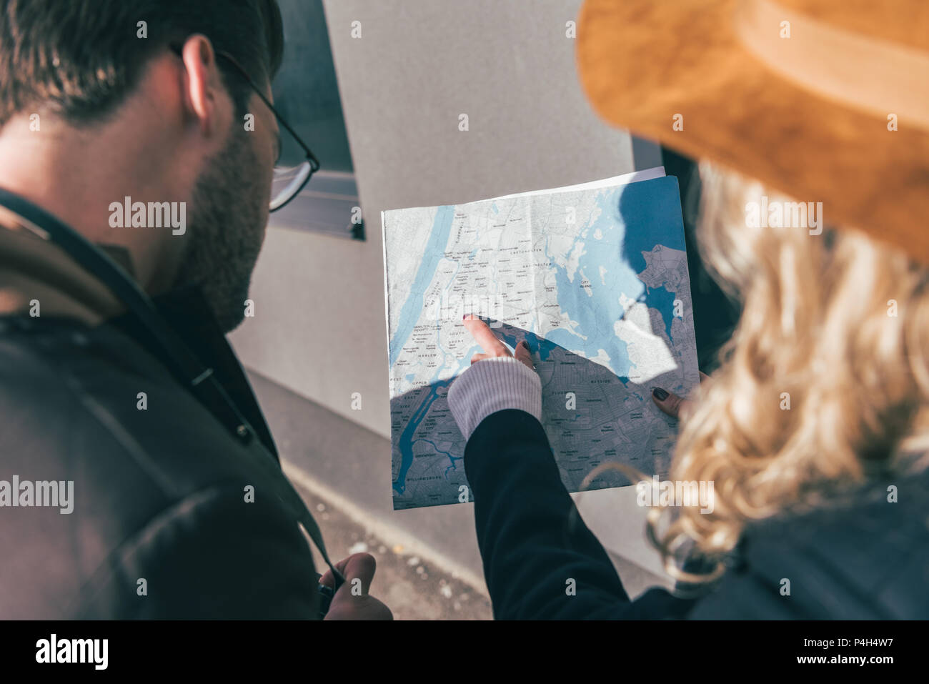 cropped shot of young couple pointing at map while standing together on ...