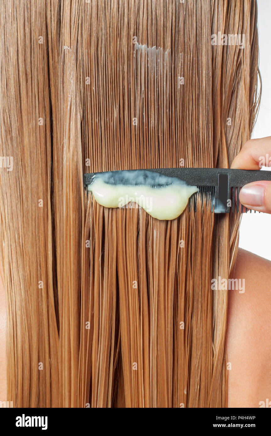 Hair care. Woman with comb is applying hair conditioner on her wet ...