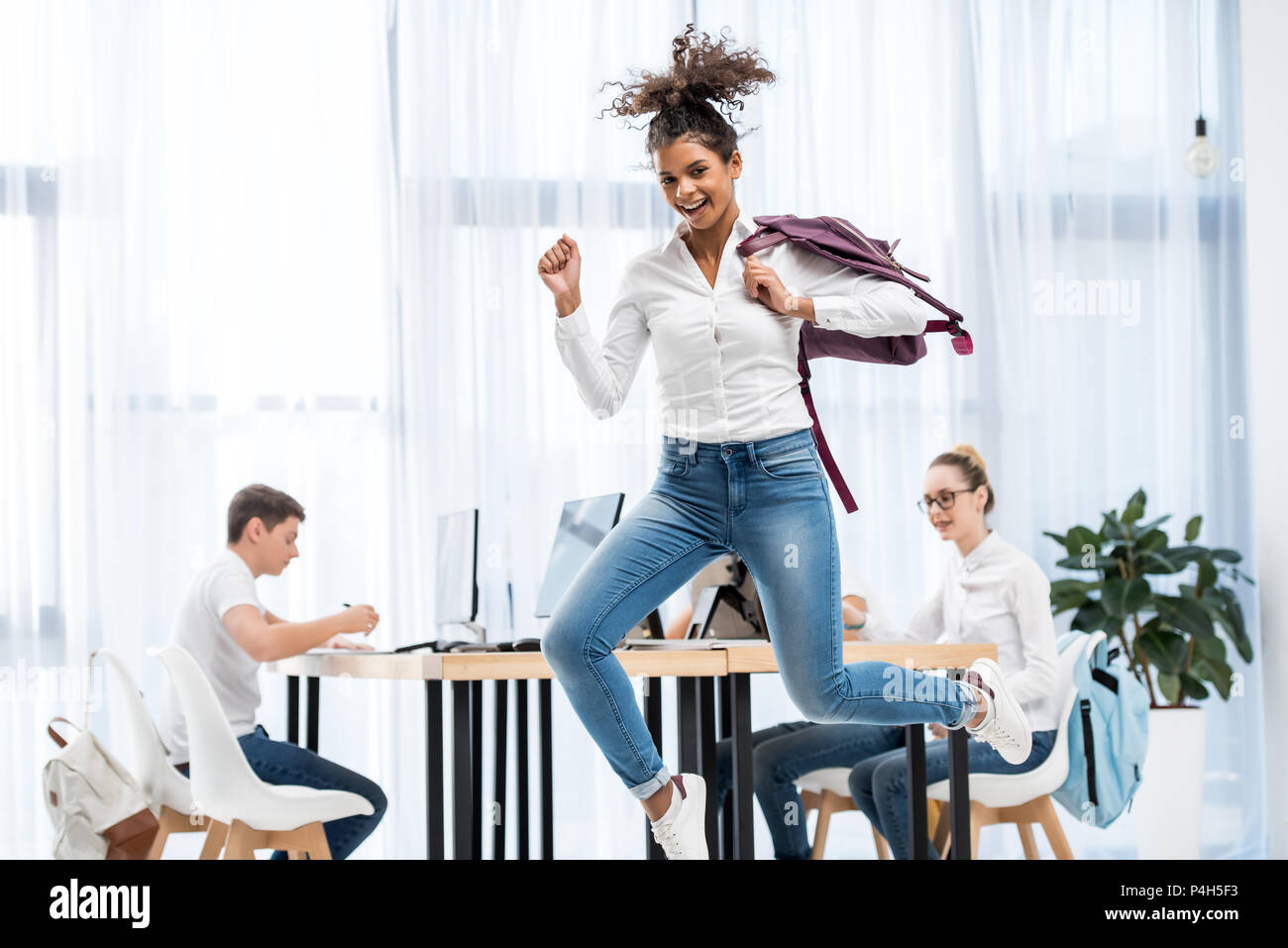 young african american student girl jumping in classroom with friends ...