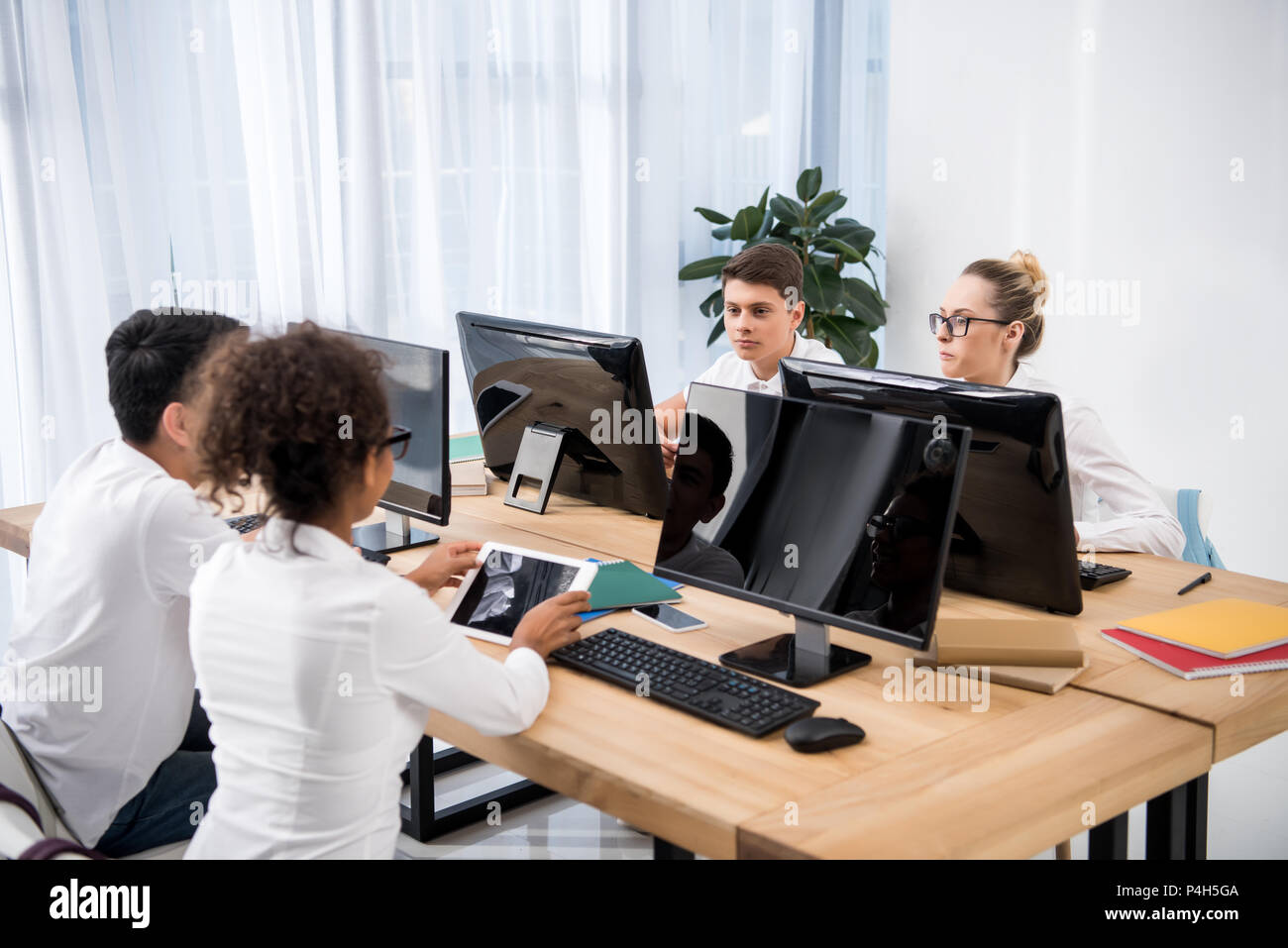 four young multicultural students studying on computers Stock Photo - Alamy