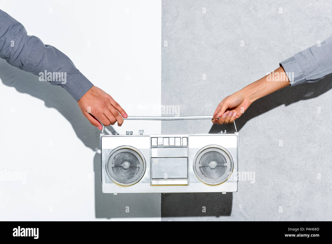 Close-up view of young couple holding boombox in hands on grey and ...