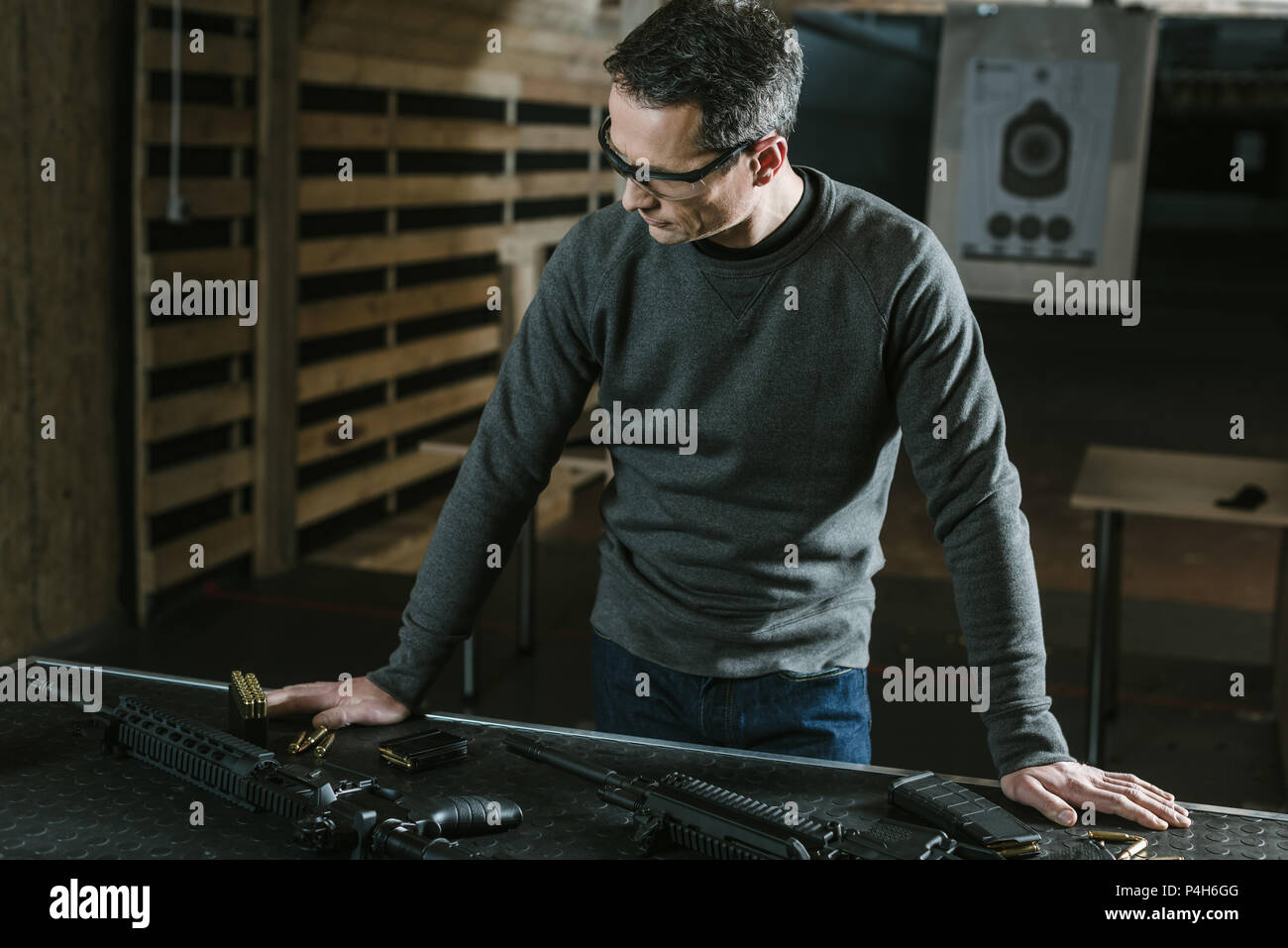 handsome man leaning on table with weapons in shooting range Stock ...
