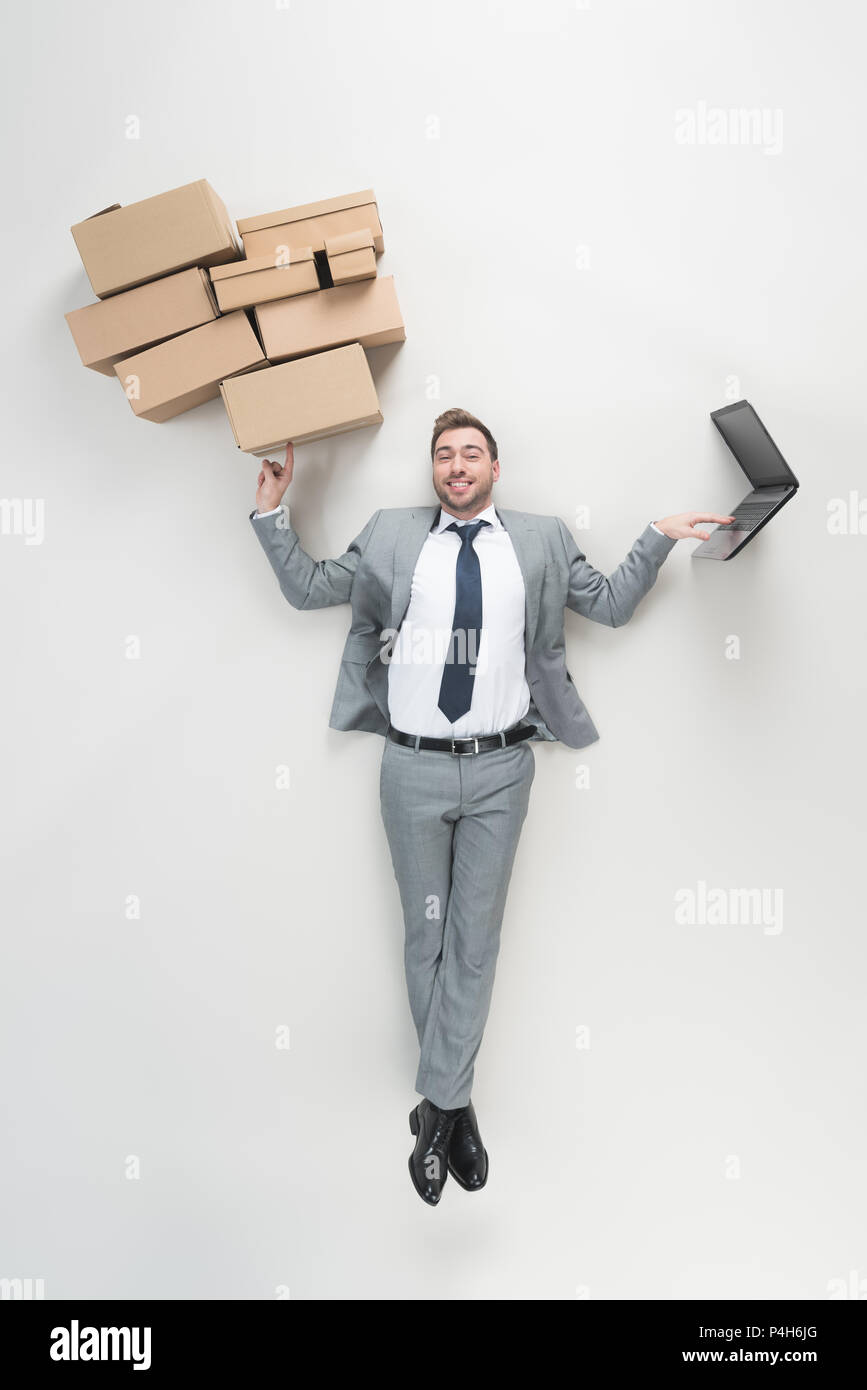 overhead view of businessman holding cardboard boxes and using laptop ...