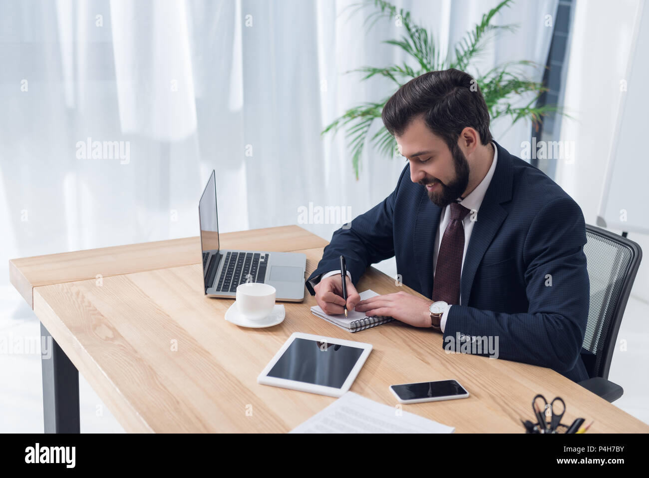 side view of businessman making notes in notebook at workplace in ...